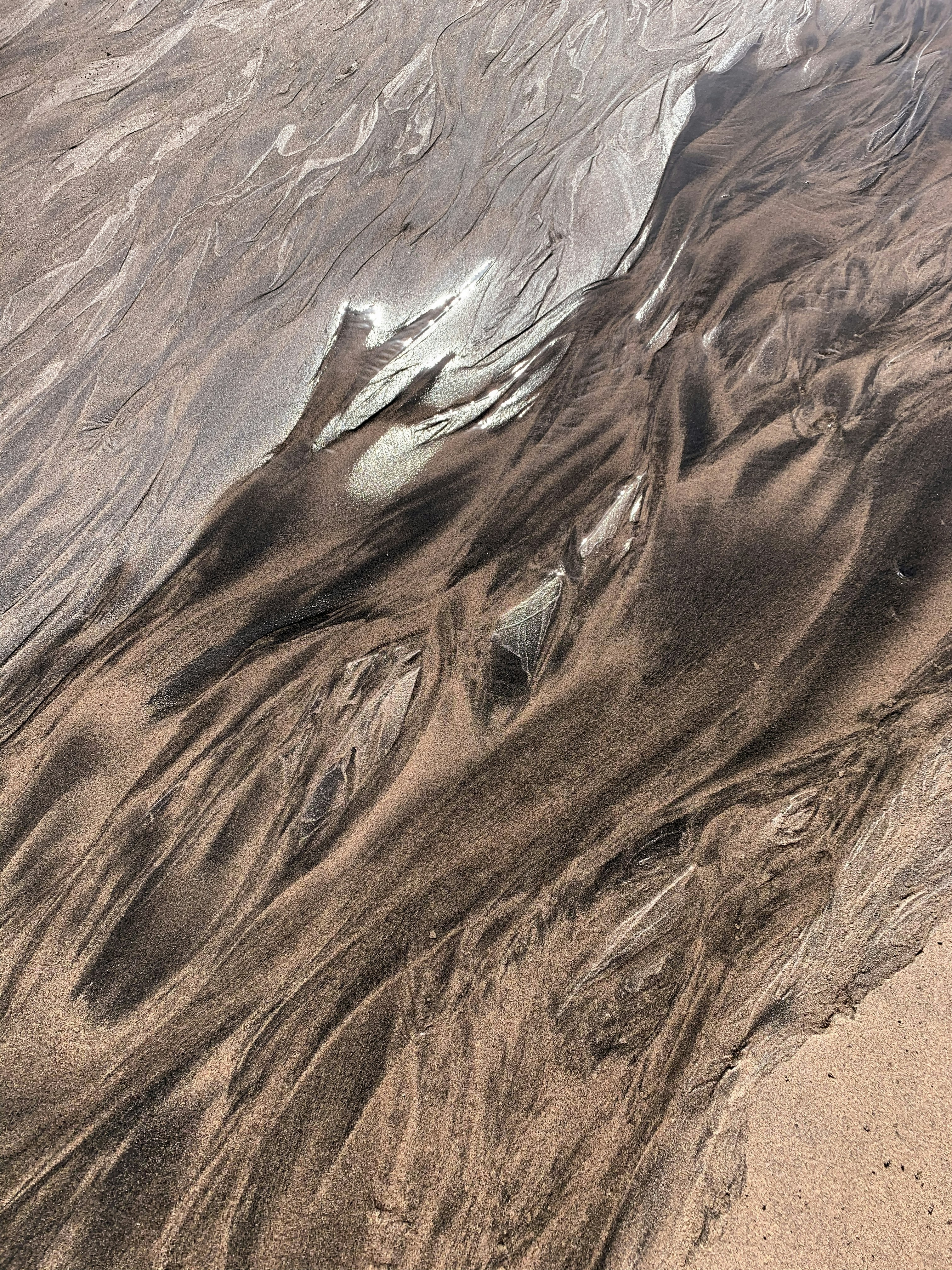 Volcanic coloured sand, shaped by the paths of the water flowing to the ocean. | brown and gray rock formation