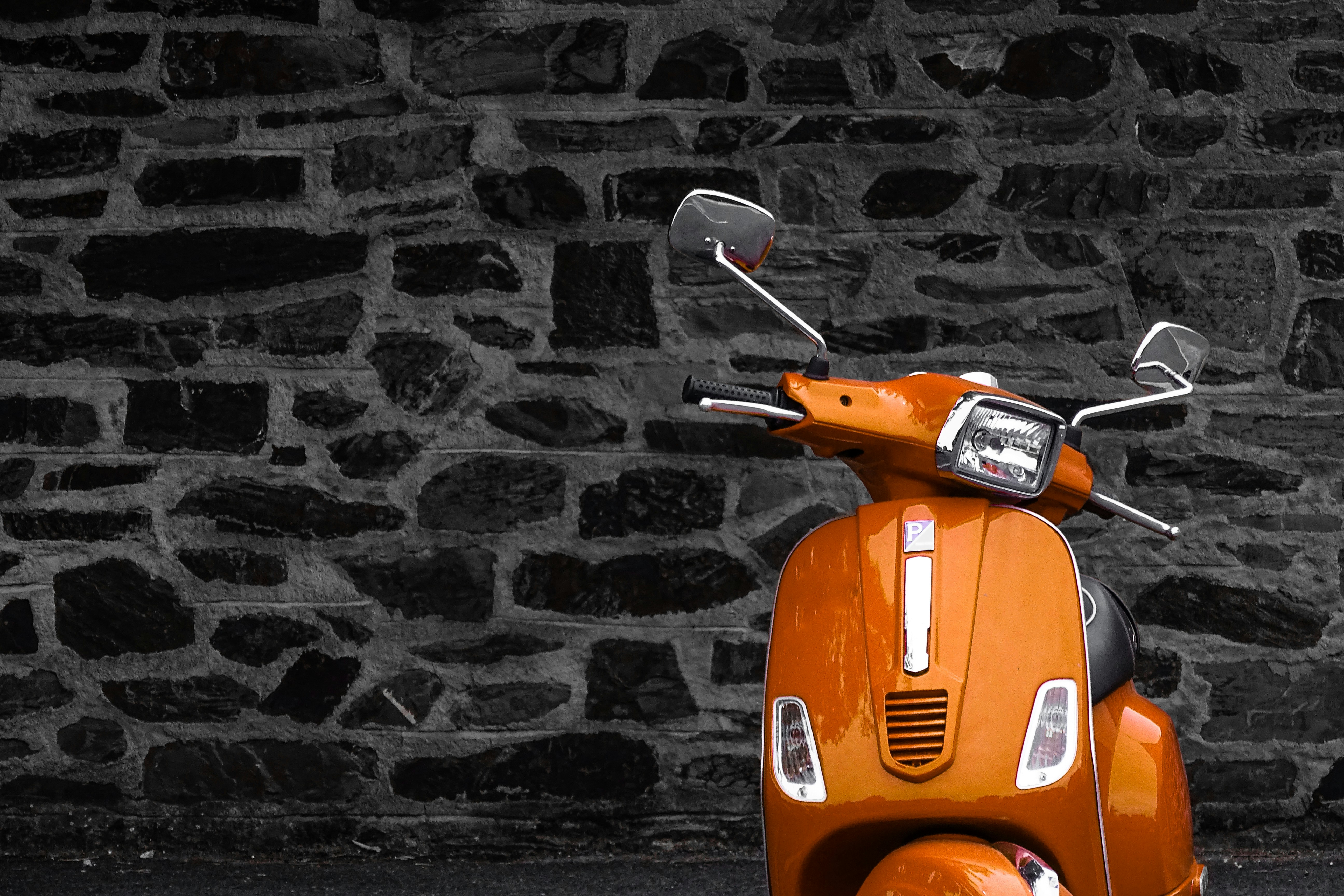 Orange vespa scooter | orange motor scooter parked beside black and white wall