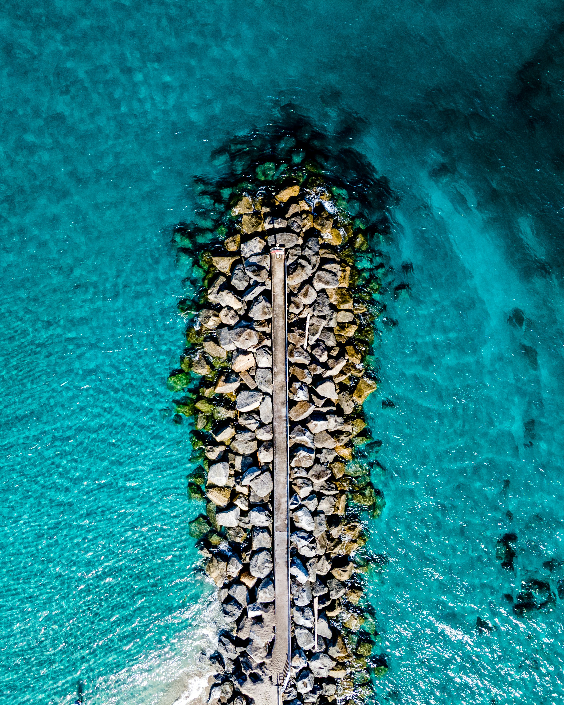 Stone Spine in Turquoise Tide: Aerial Breakwater Piercing the Sea