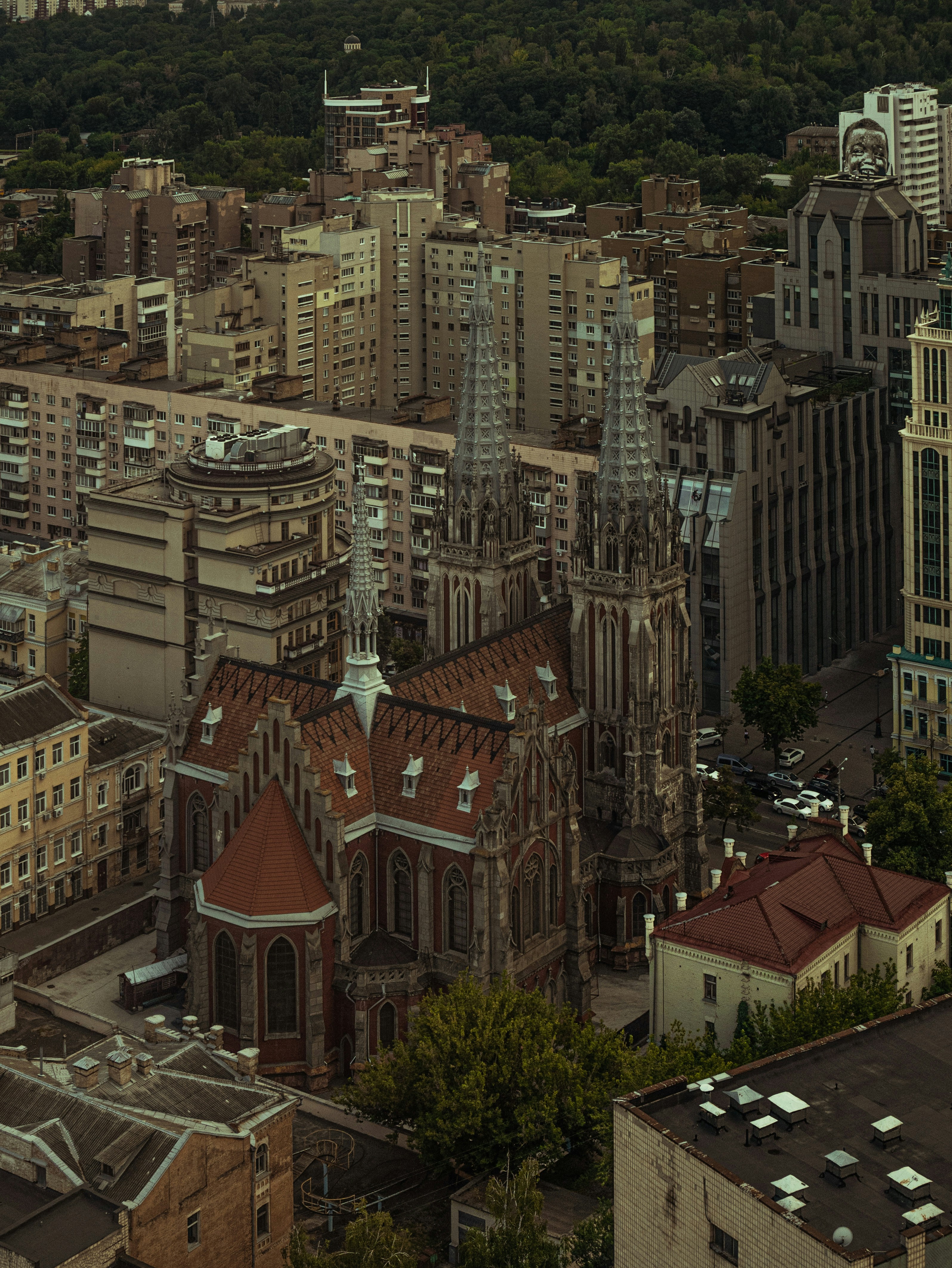 Gothic-style church with intricate spires nestled among modern city buildings, showcasing a blend of architectural styles. The scene captures the contrast between historical and contemporary structures.