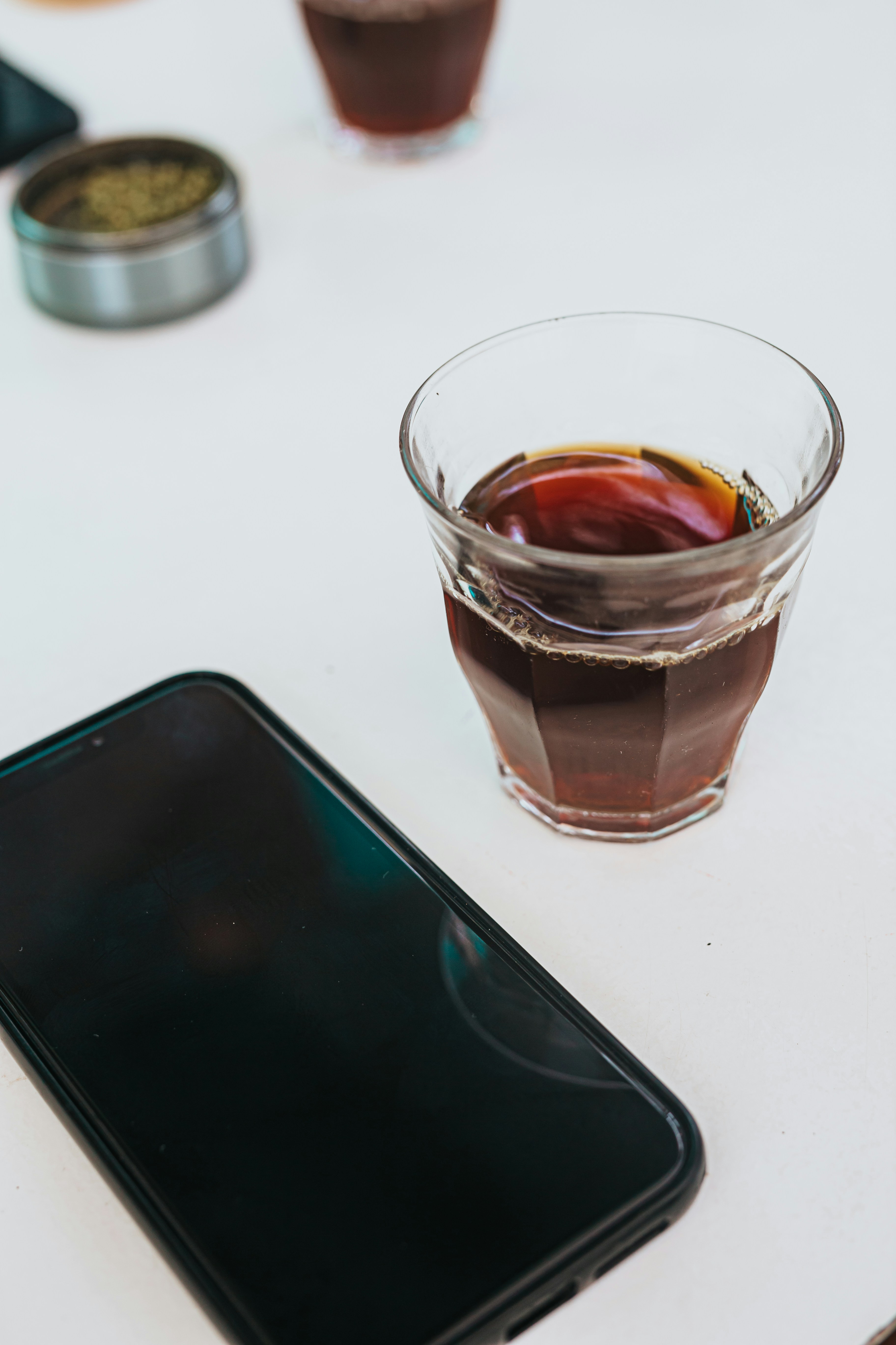 clear drinking glass beside black android smartphone