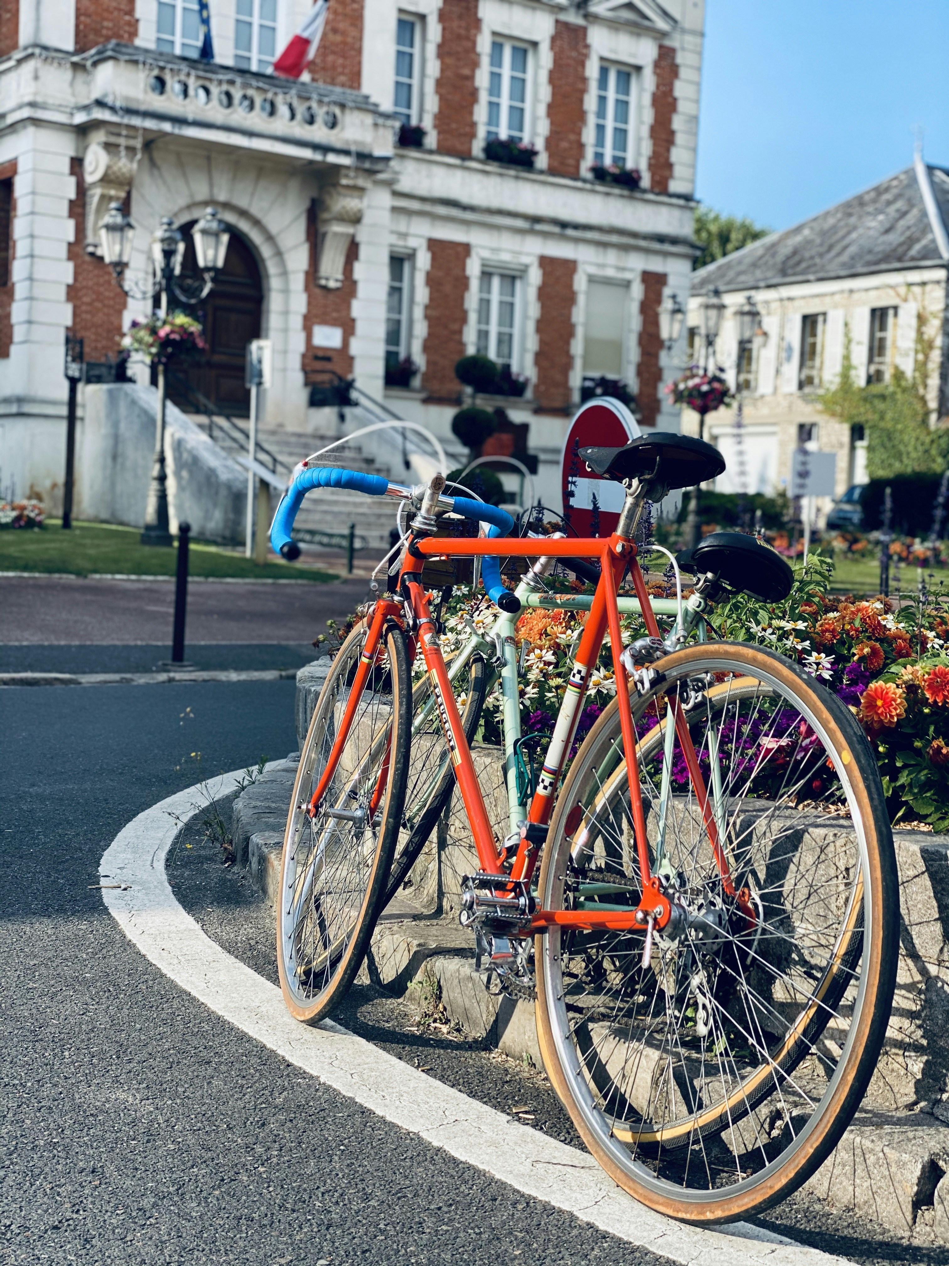 Orange bicycles leaning by a flowerbed in a town square