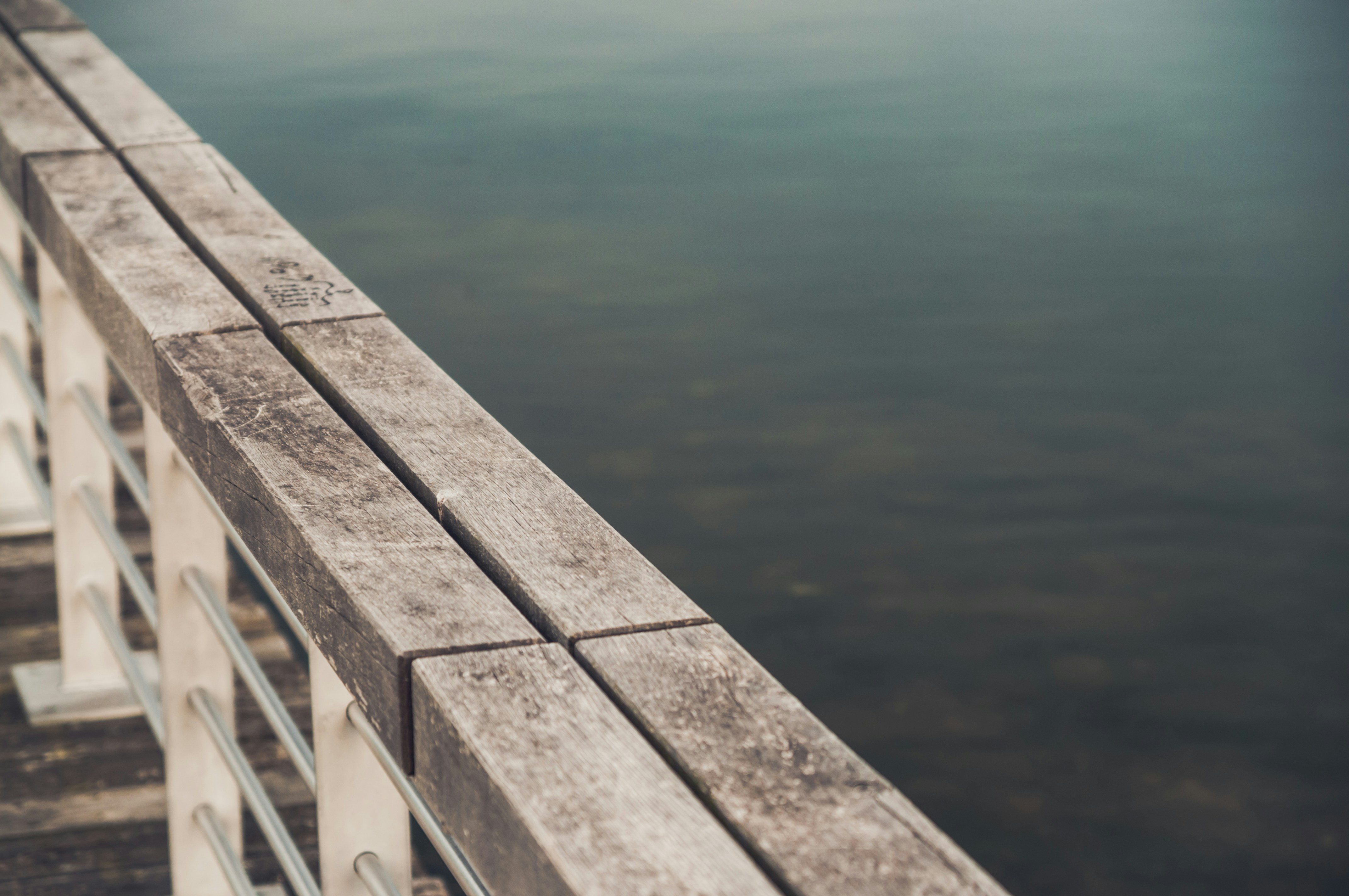 Weathered wooden railing leading to calm water, evoking a sense of serenity and contemplation.