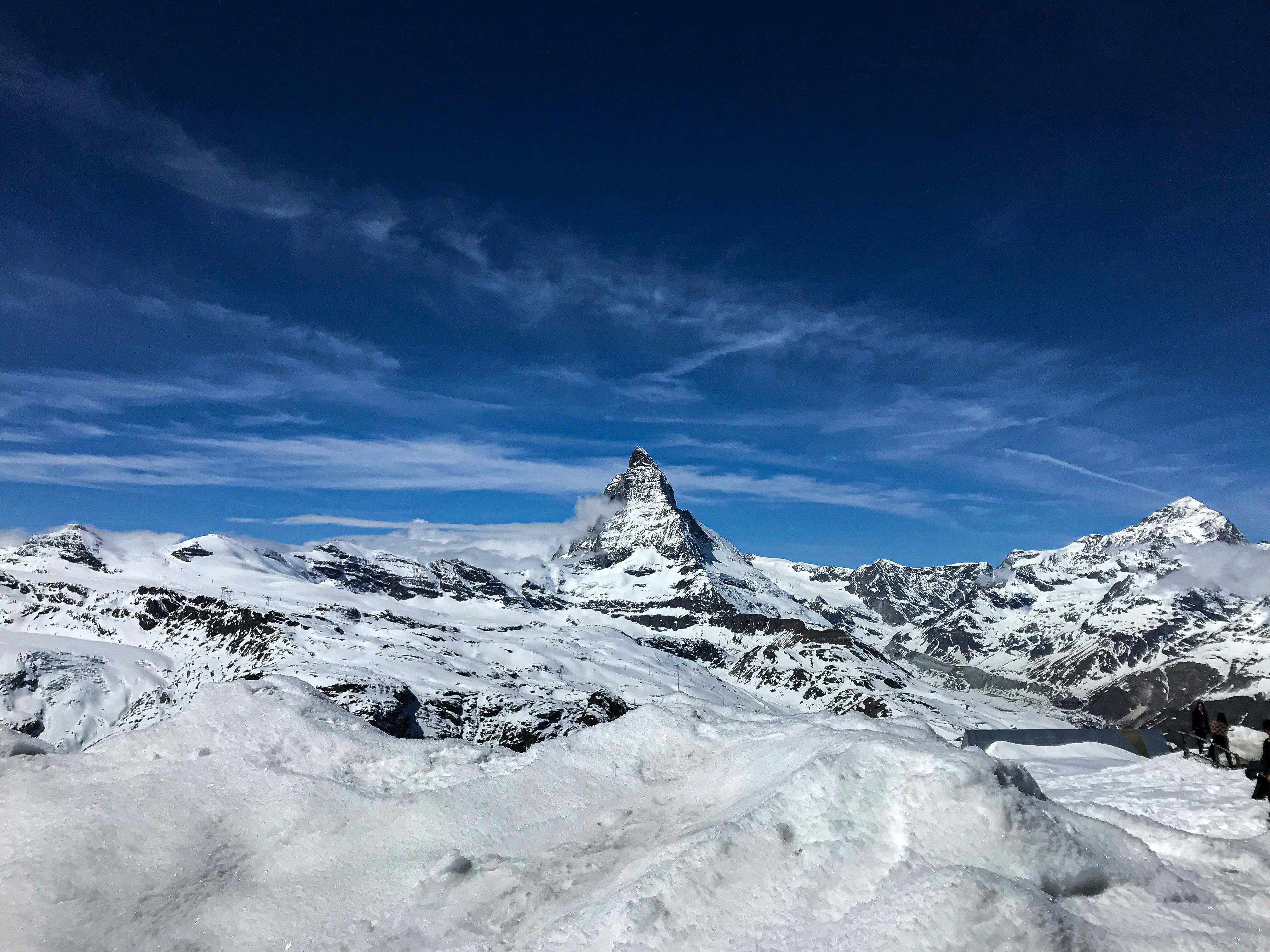 Snow-covered mountains under a clear blue sky, with the iconic Matterhorn towering in the background. The scene captures the serene beauty of a winter landscape.