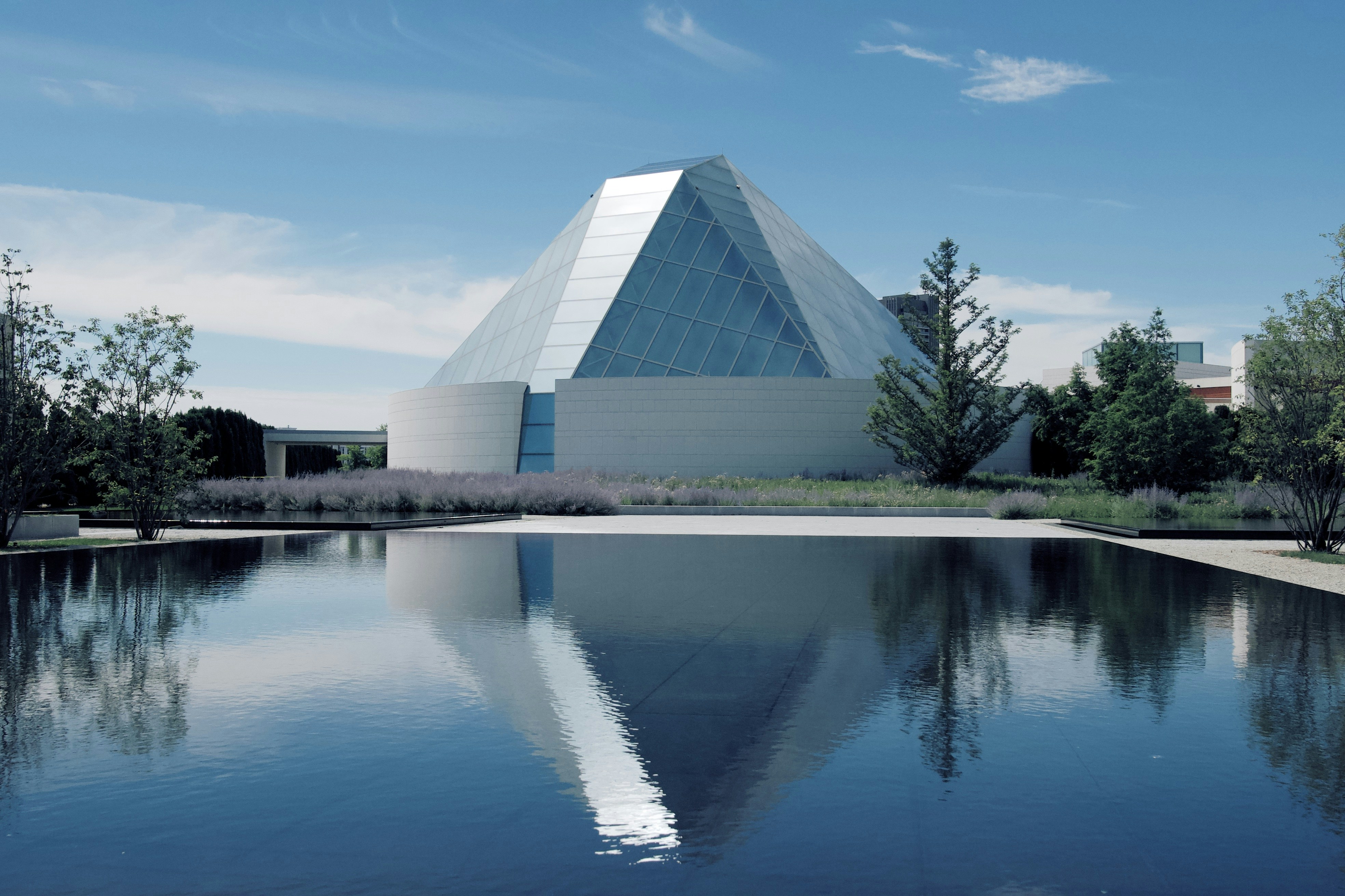 White and gray pyramid building near green trees and body of water ...