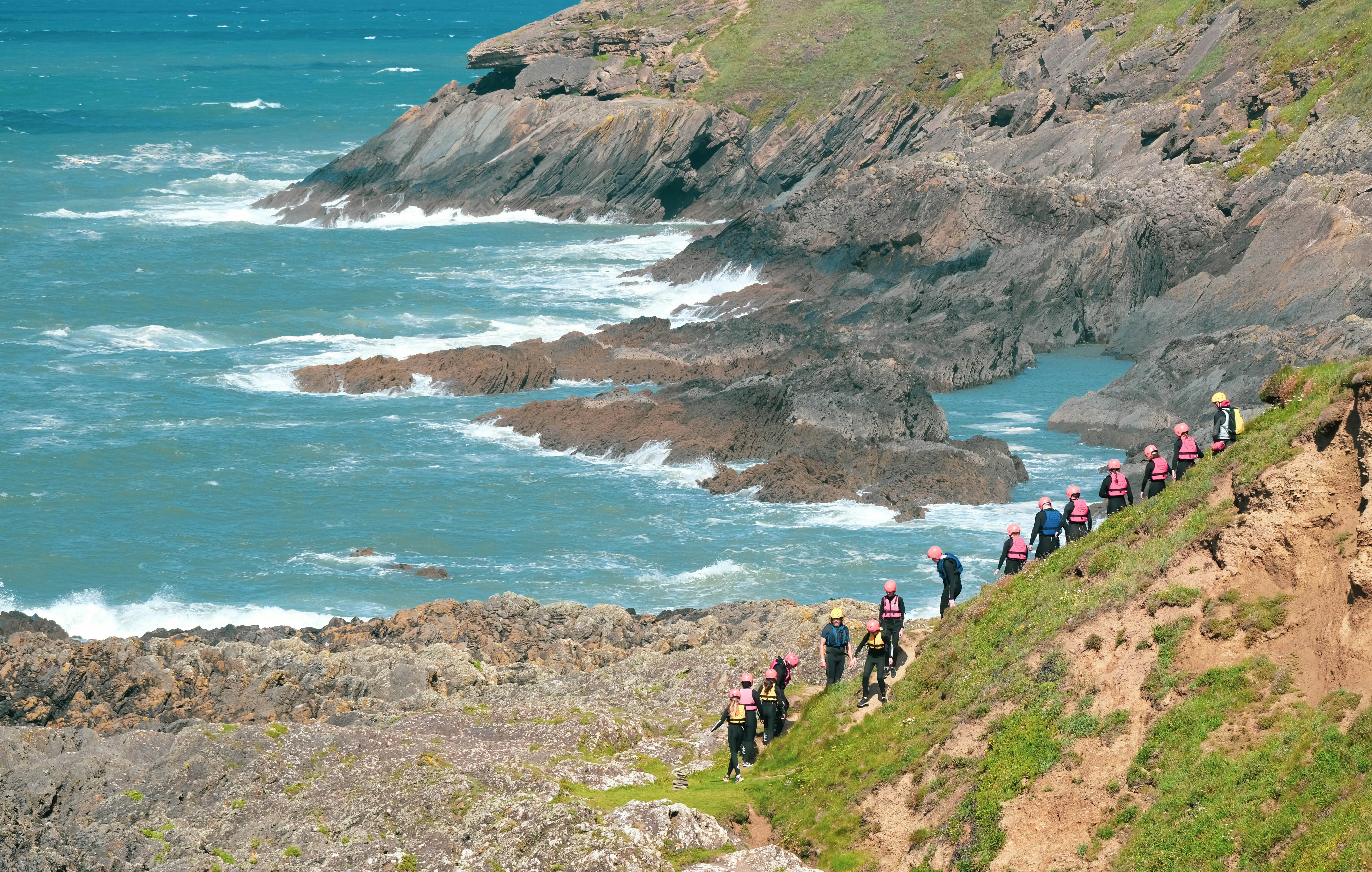 Coastal Trail in Motion: Row of hikers Climbing a Weathered Cliff