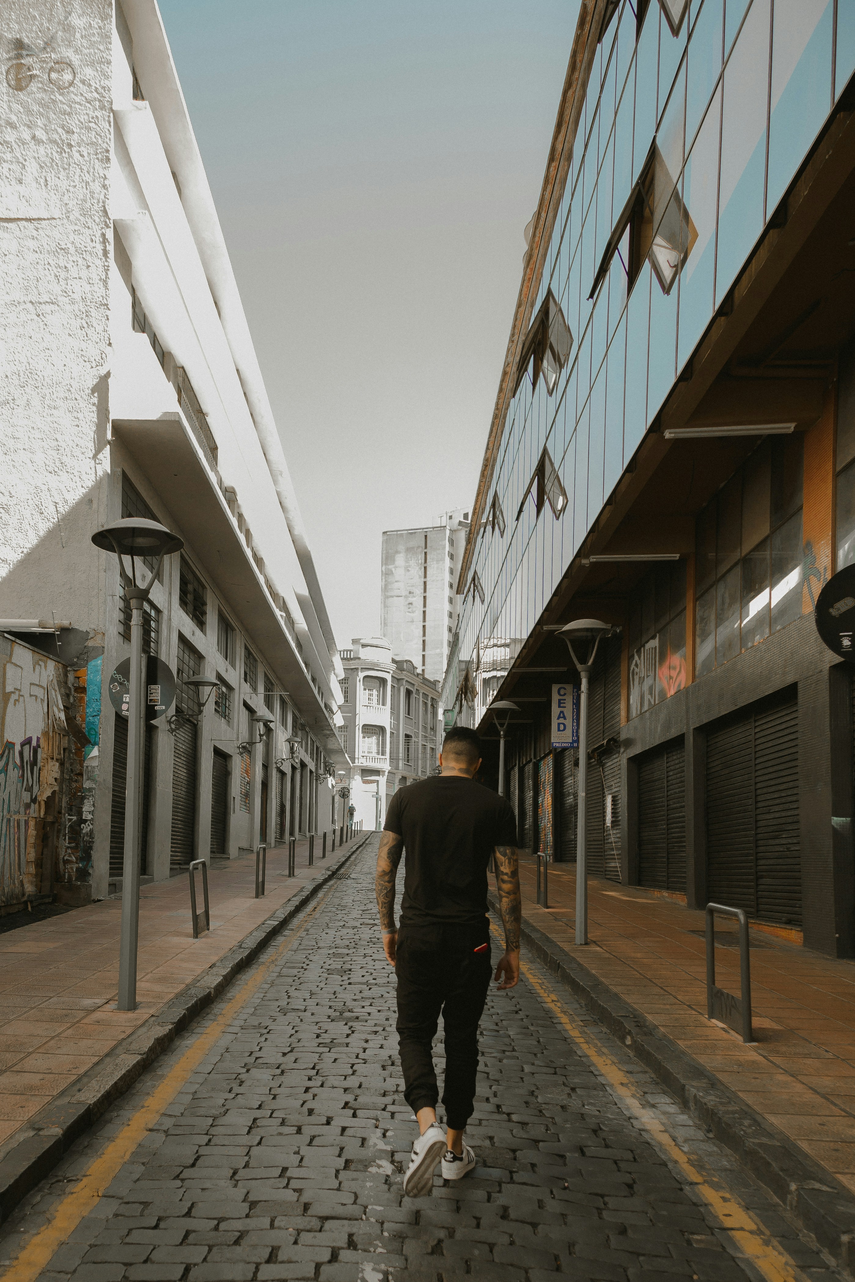 Stride Between Stone and Glass: A Lone Walker Amid Two Urban Facades