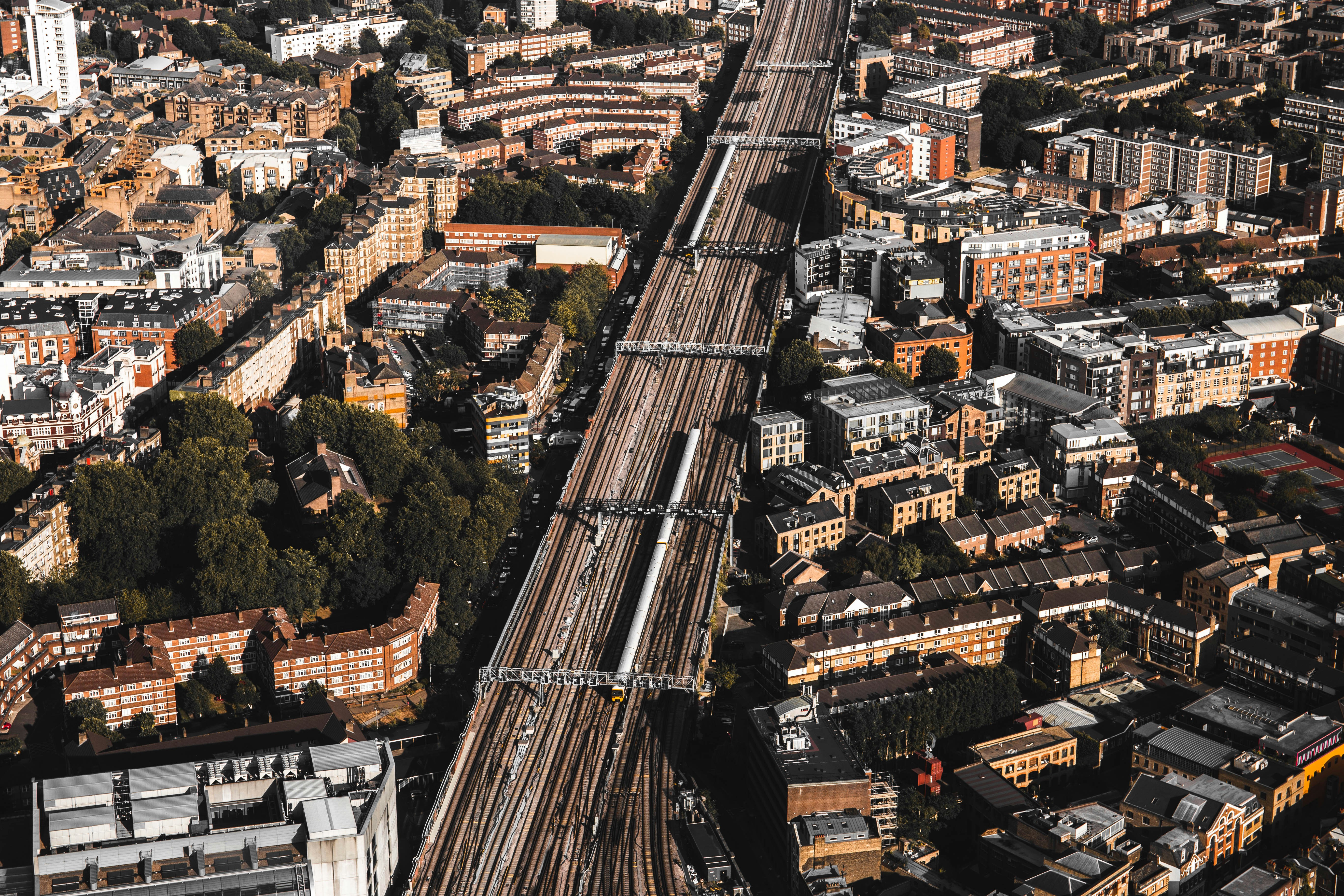 Aerial view of railway tracks weaving through a bustling urban landscape, showcasing the intricate relationship between transportation and city architecture.
