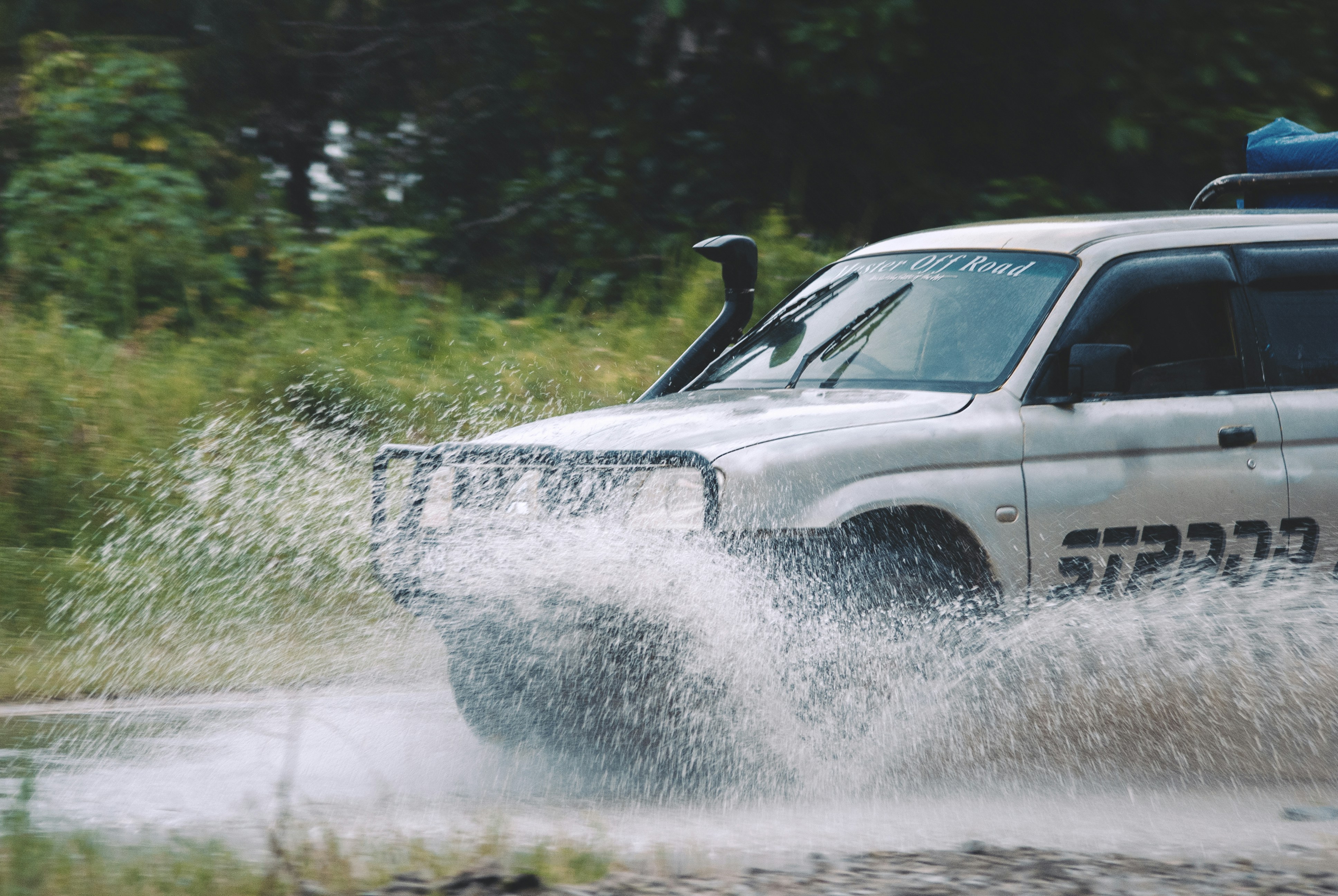 Flooded Forest Road Patrol: White Pickup Splashes Through Water Spray