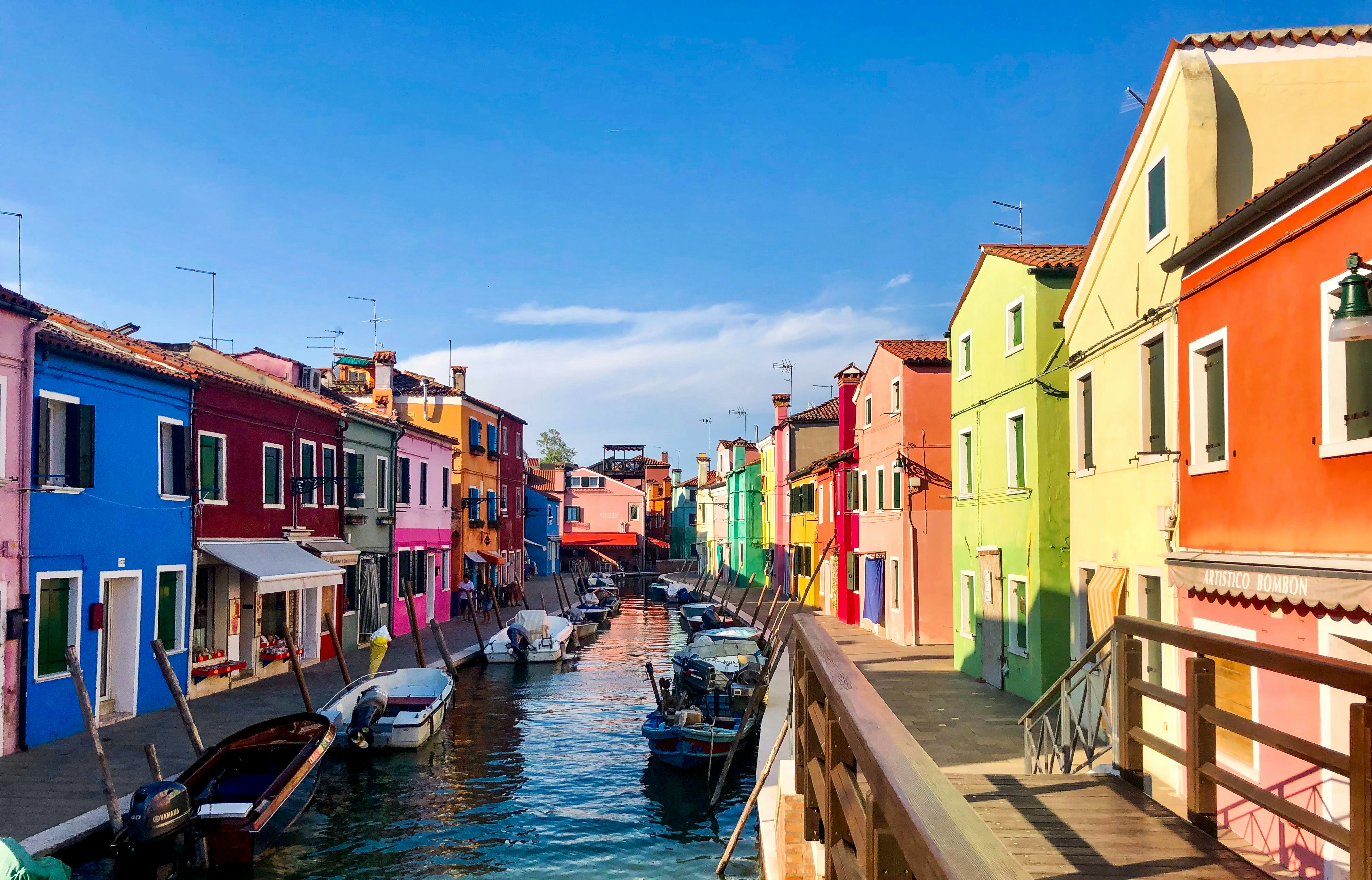 Colorful houses line a canal under a clear blue sky in a picturesque town.