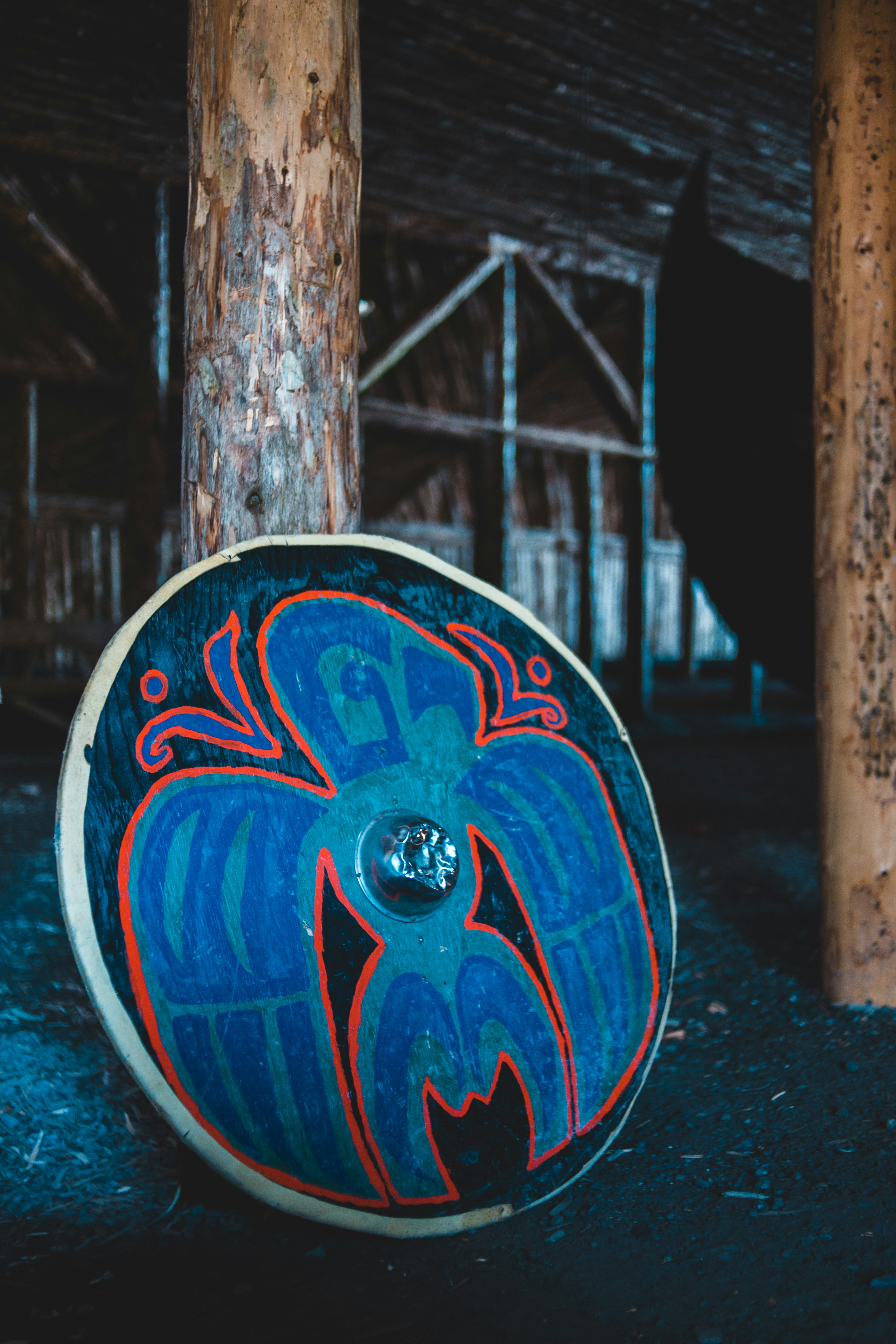 Masked blue glyph leaning against a wooden pillar in a dark, abandoned space