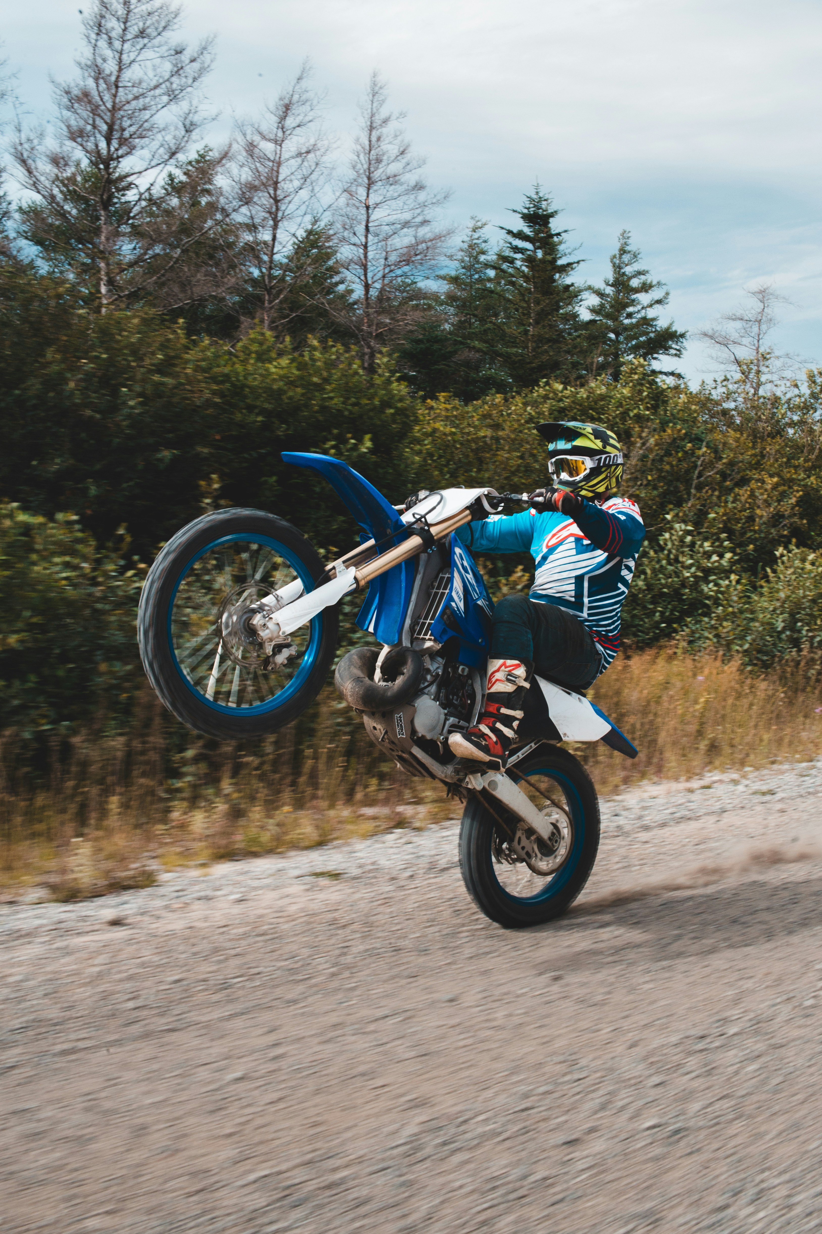 Man in white and blue racing suit riding blue motocross dirt bike photo ...