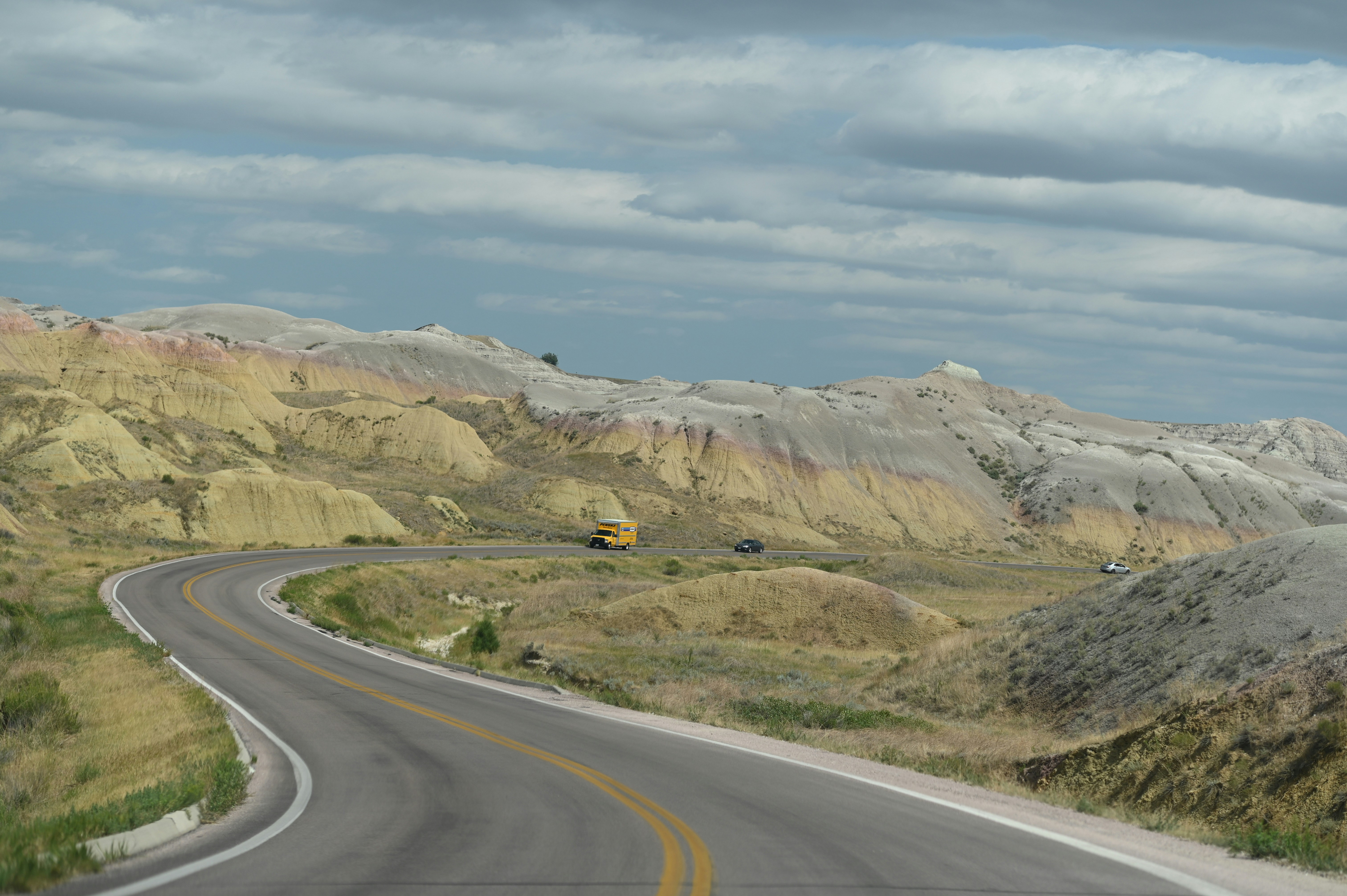 Gray asphalt road near brown mountain under white clouds during daytime ...