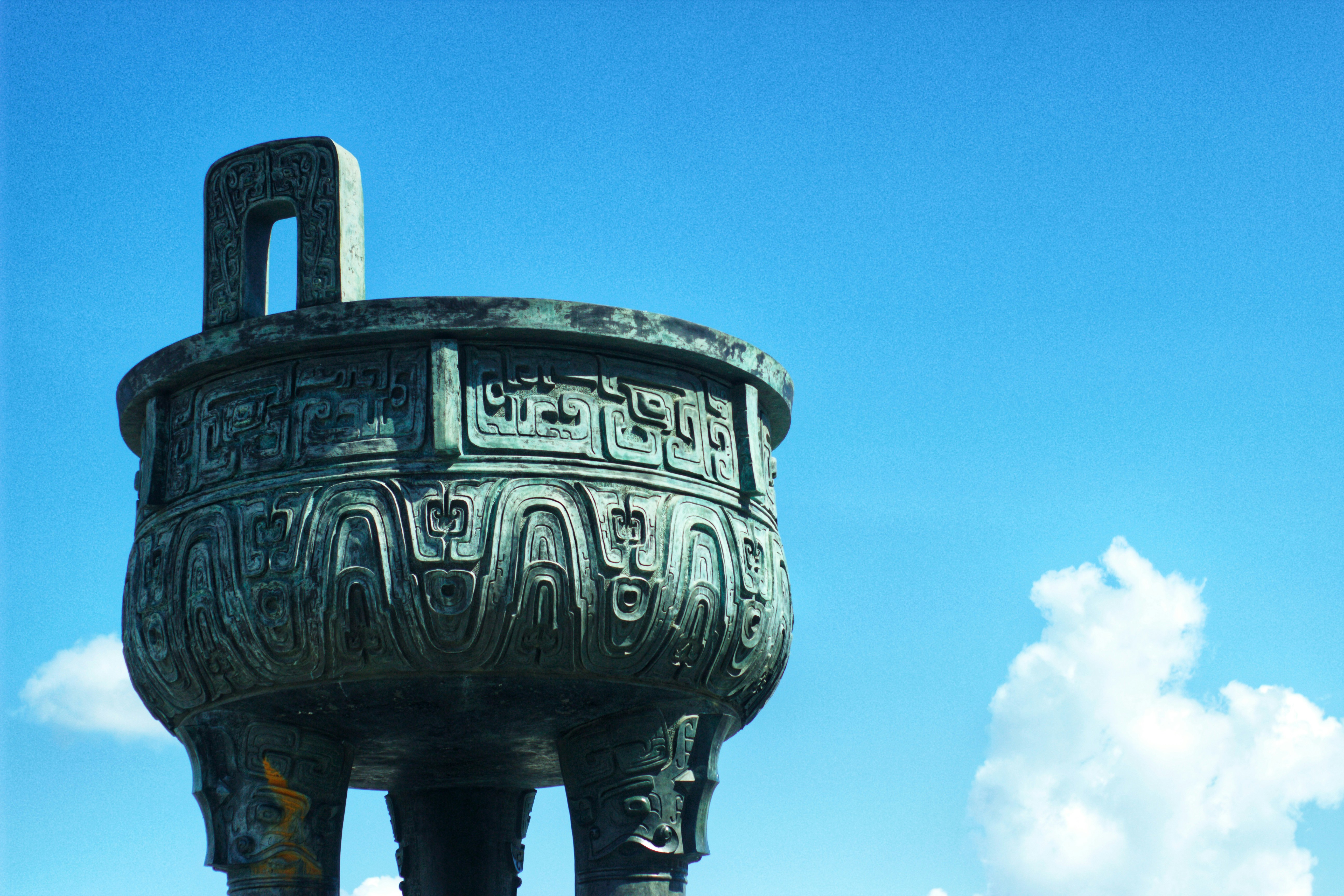 Ornate Bronze Vessel Standing Against a Clear Cerulean Sky