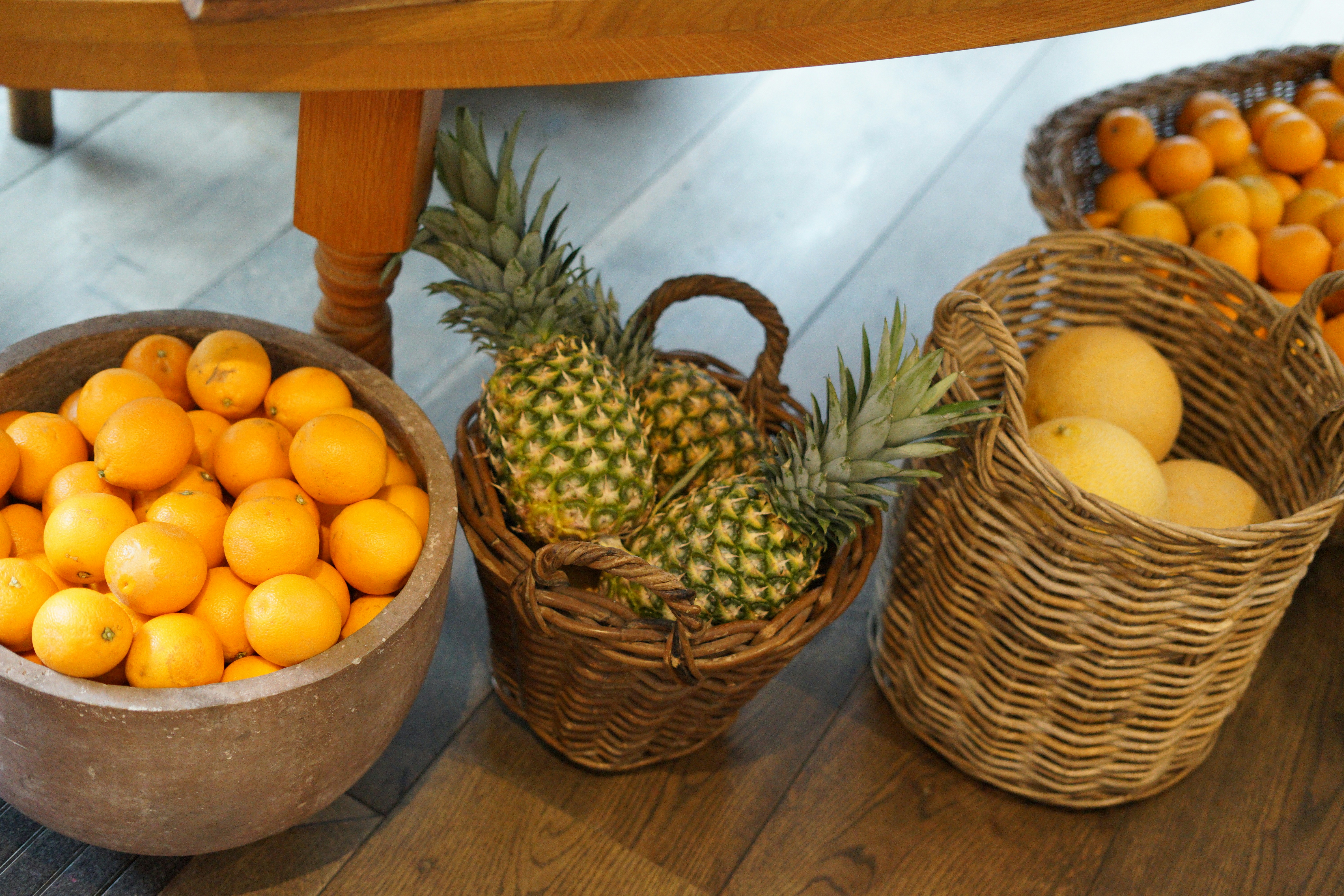 A collection of vibrant oranges, pineapples, and melons arranged in rustic baskets, showcasing a fresh harvest in a cozy setting.