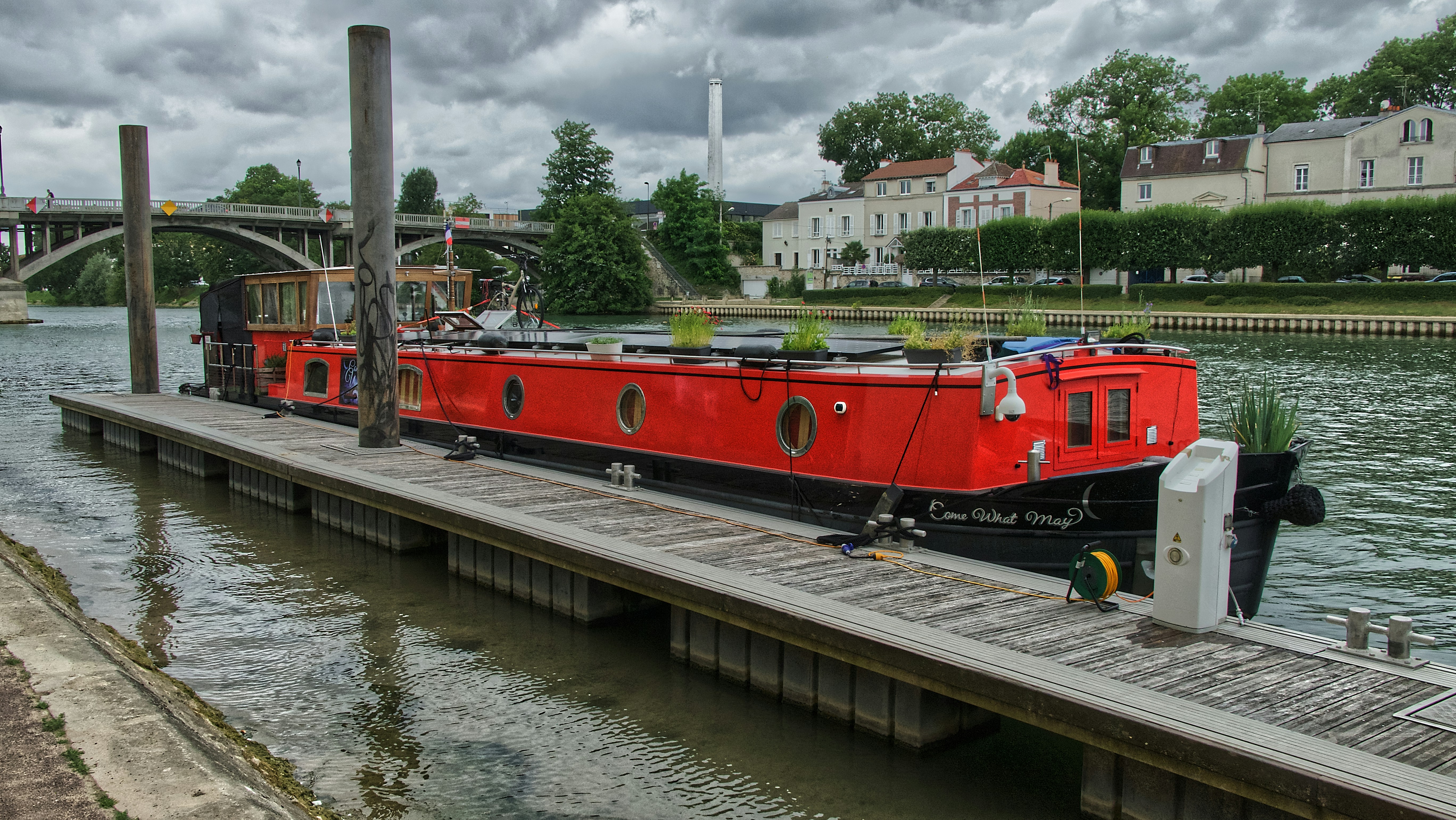 Red Canal Boat Lounges Along a Quiet Loire-like Wharf