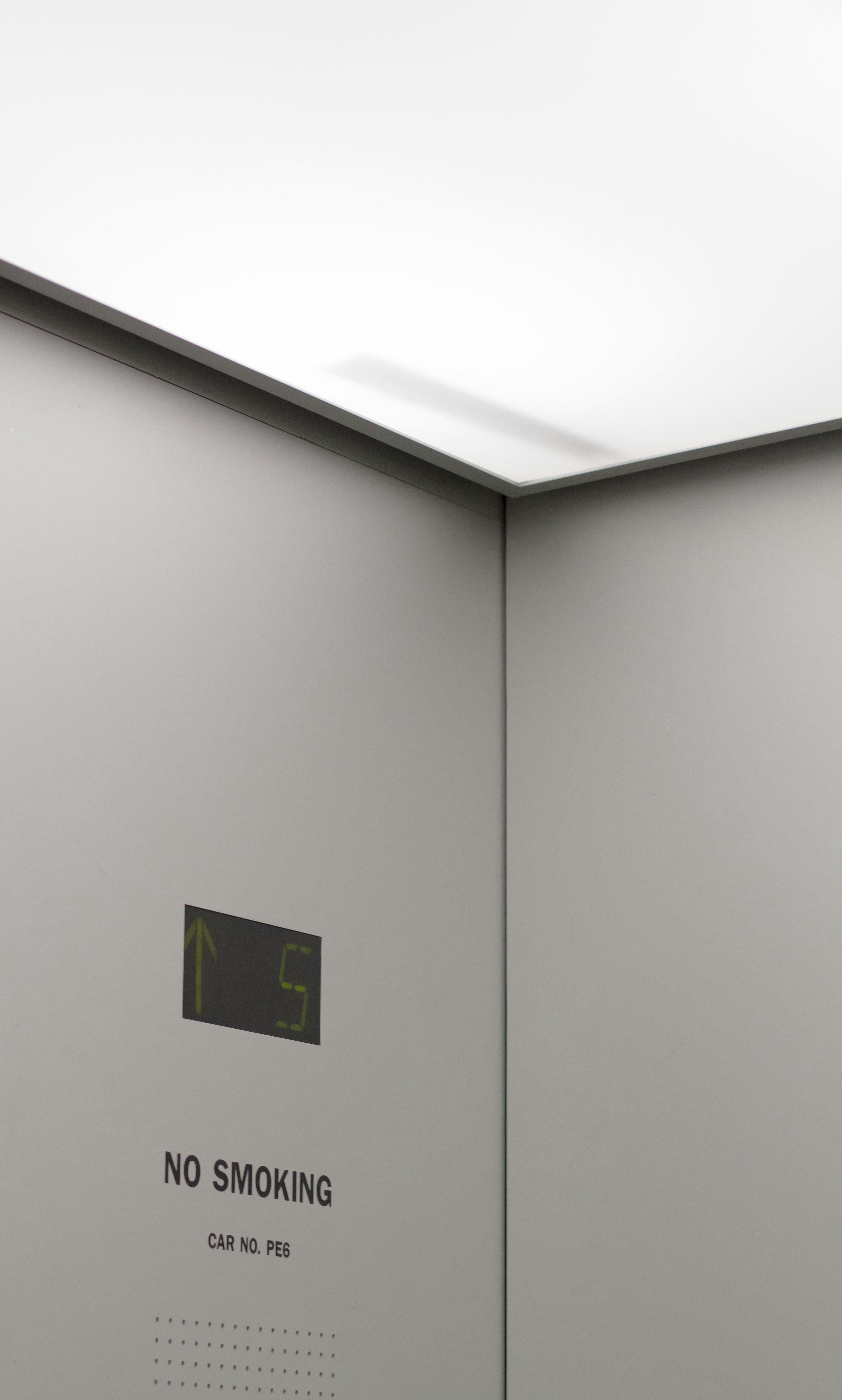 Elevator interior featuring a no smoking sign and an indicator showing the fifth floor. The design emphasizes clean lines and a modern aesthetic.