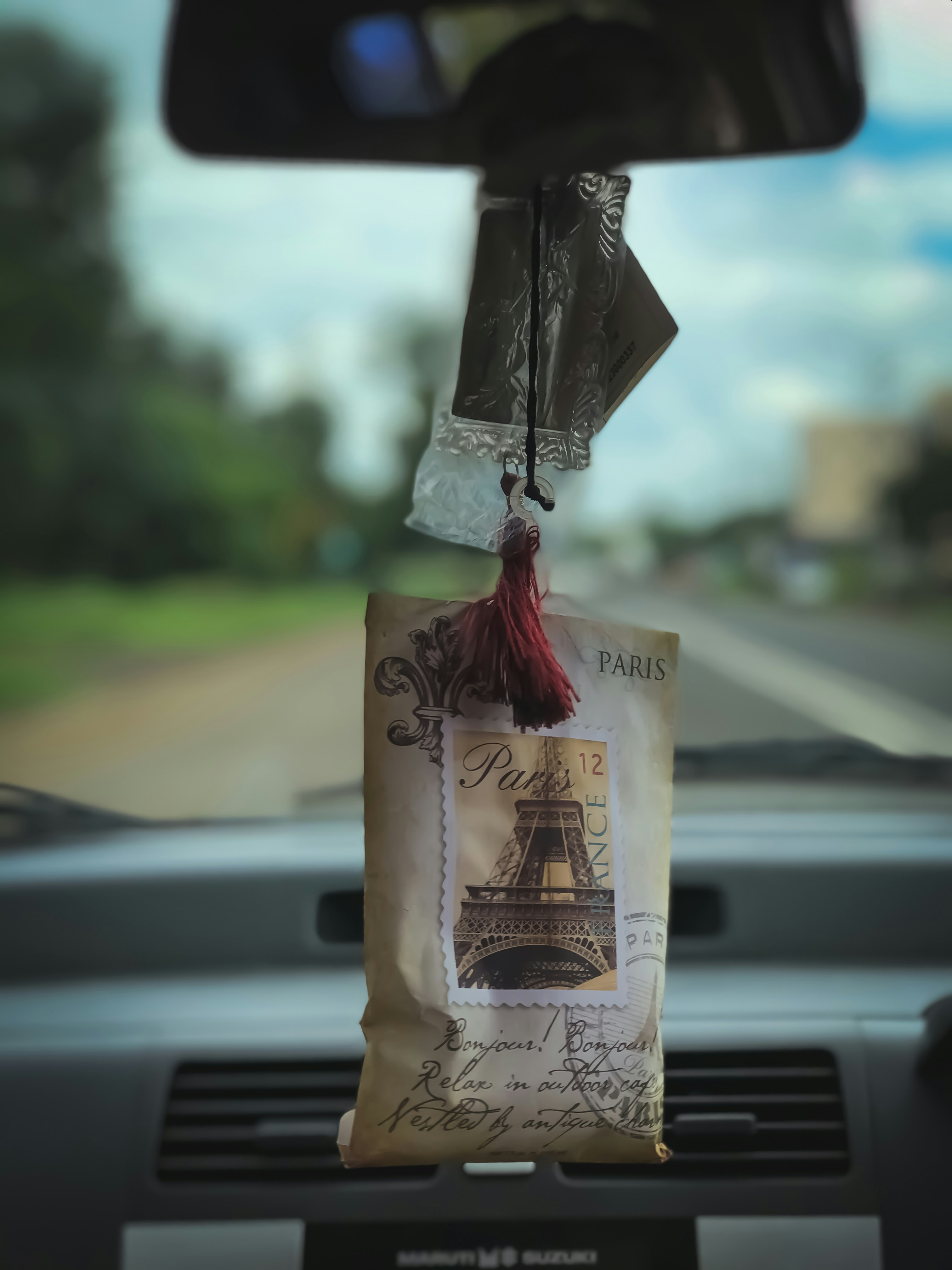 Parisian sachet dangling from the rear-view mirror in a sunlit car interior