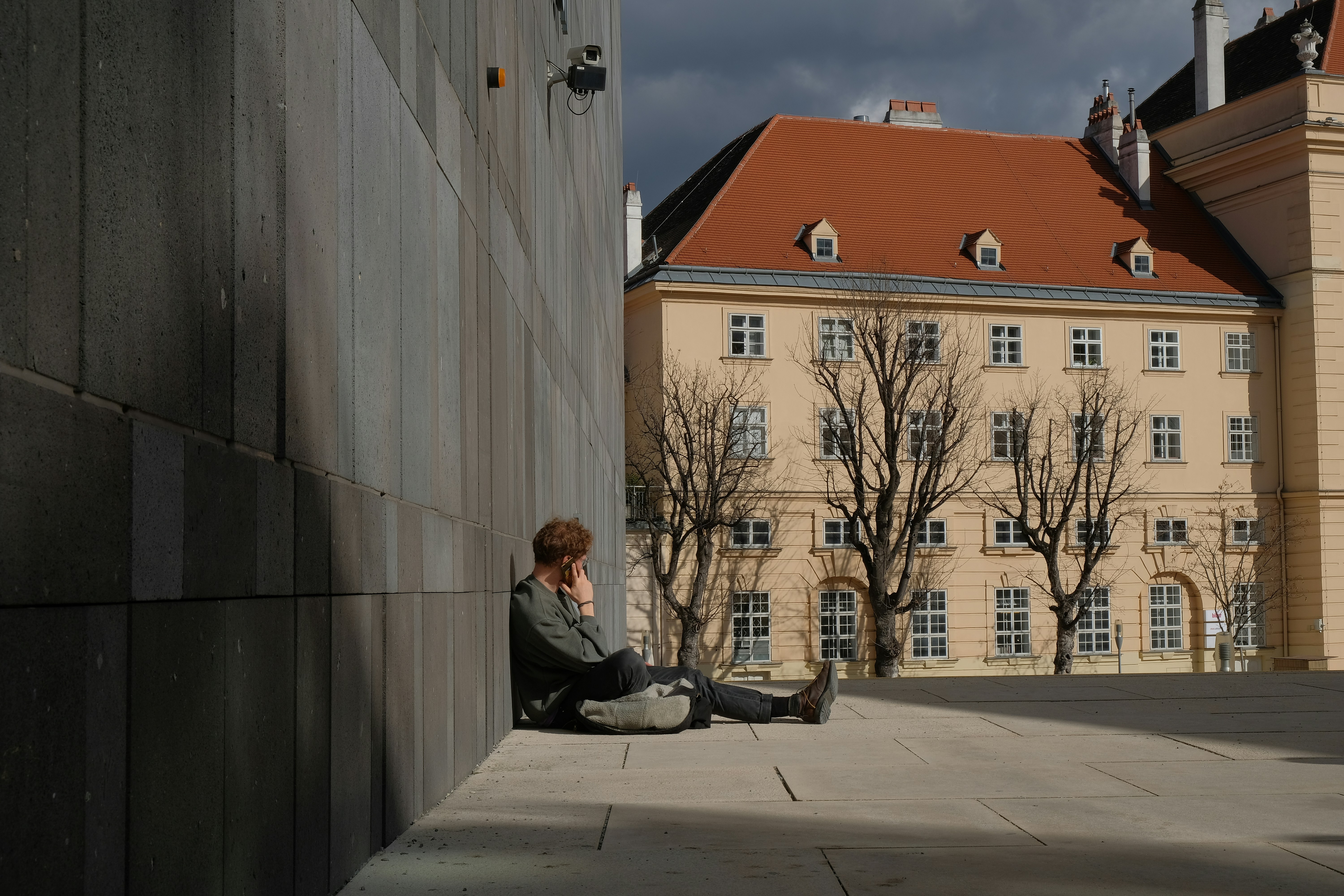 Solitary Pause by a Sunlit City Wall
