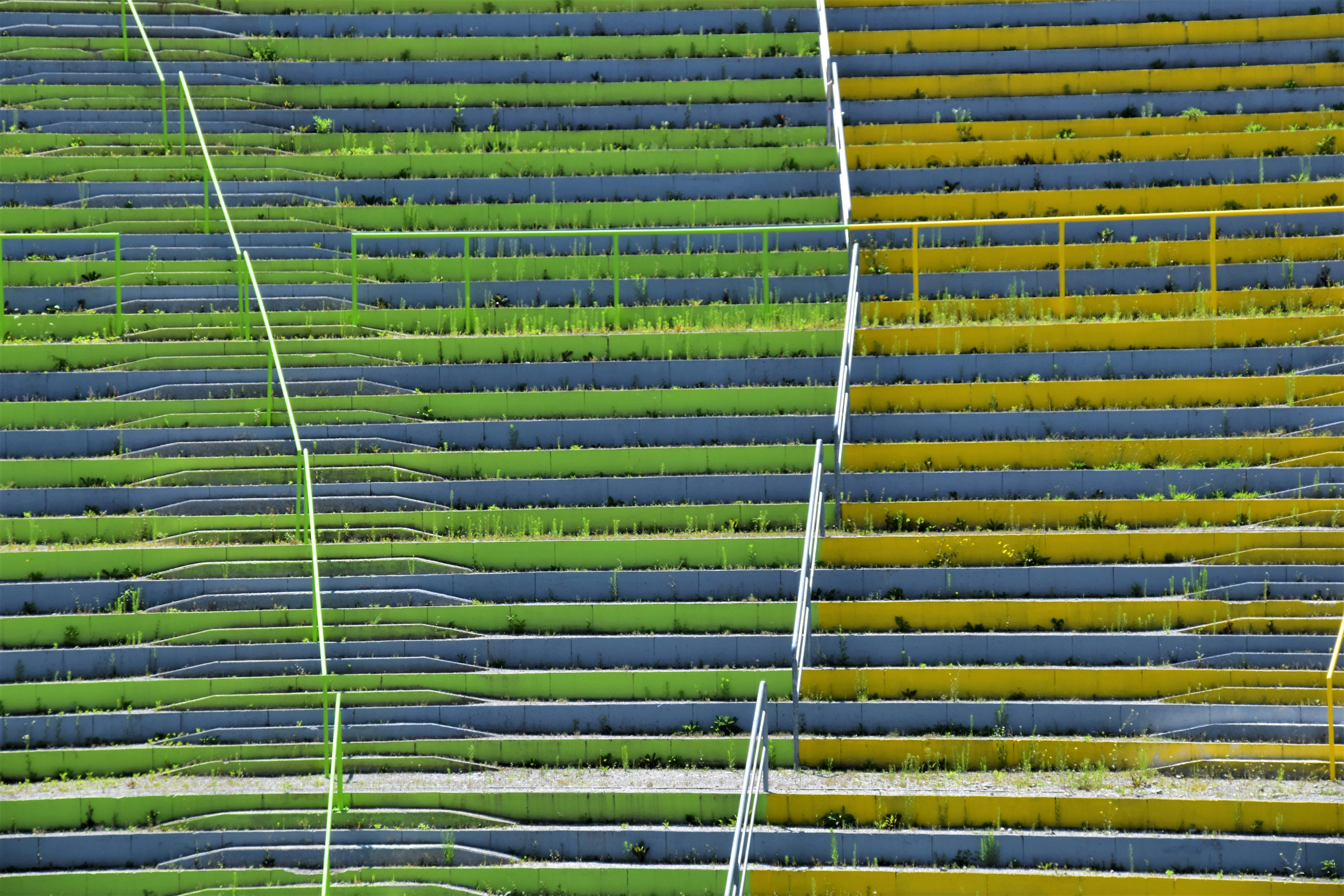 Abstract view of terraced farming showcasing alternating green and yellow rows, emphasizing agricultural design and structure.