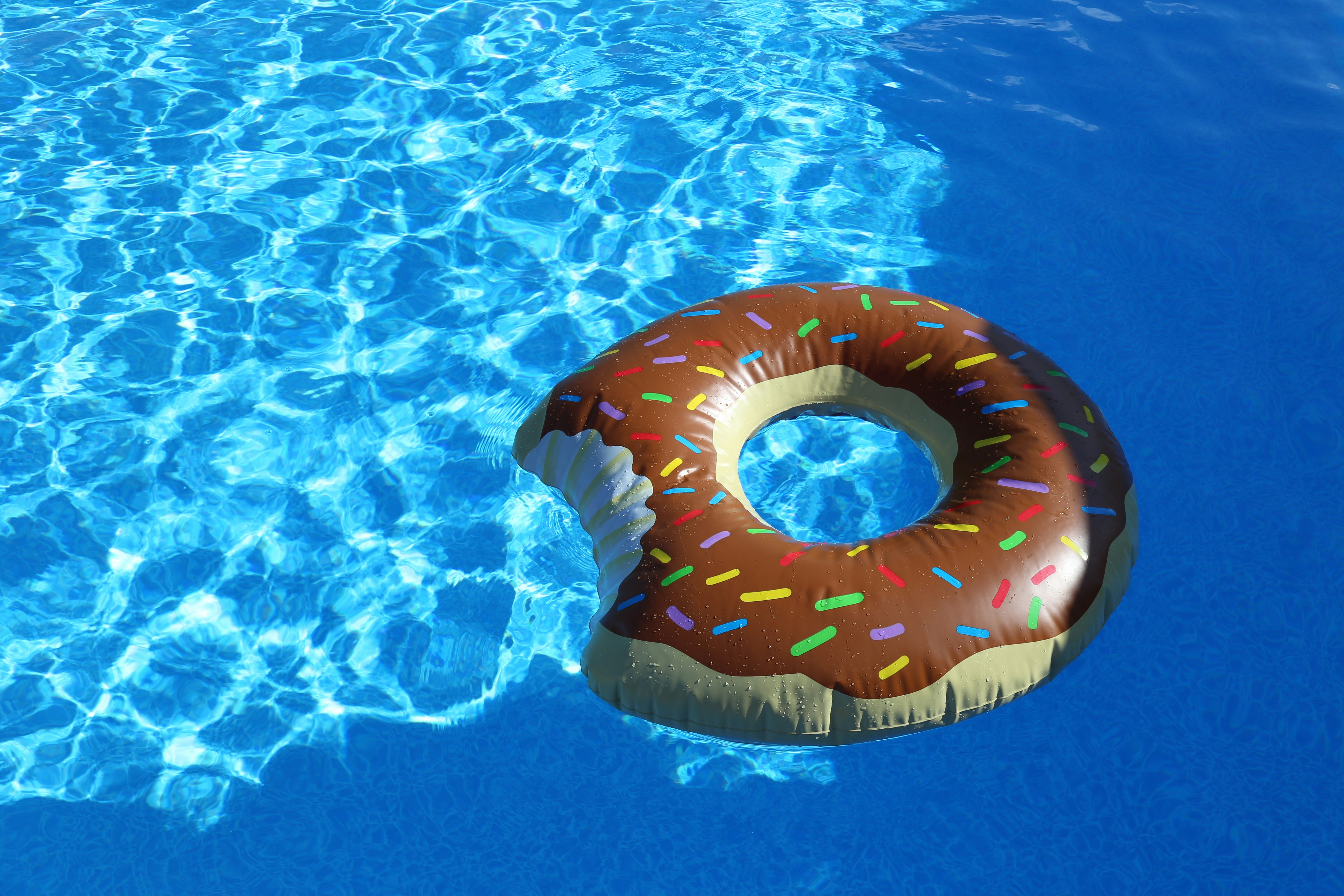 Donut Drift: Chocolate Float Gliding Over a Sunlit Pool