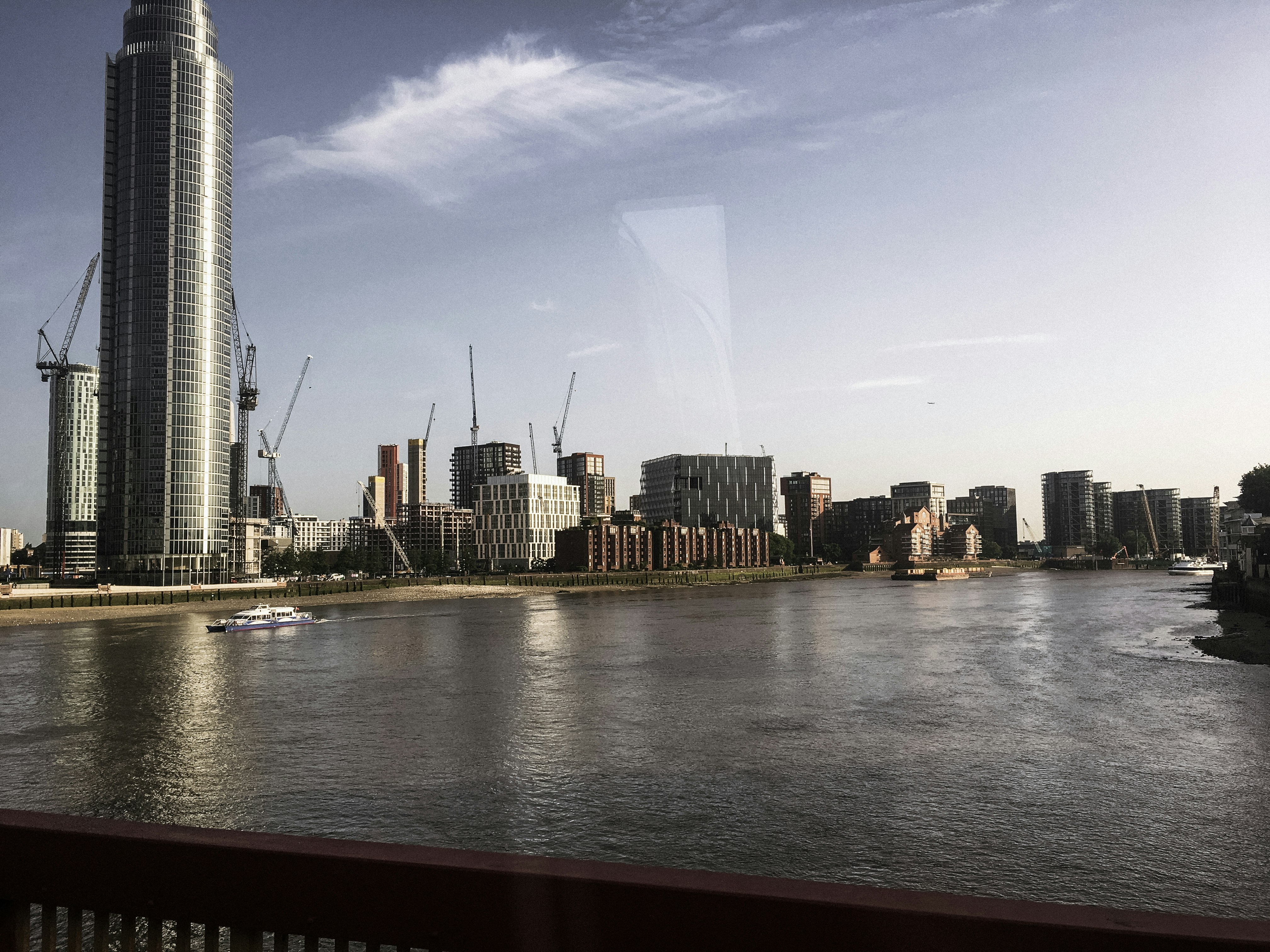 Crane-lit Glassline: A Riverfront Skyline Emerges Over Calm Water