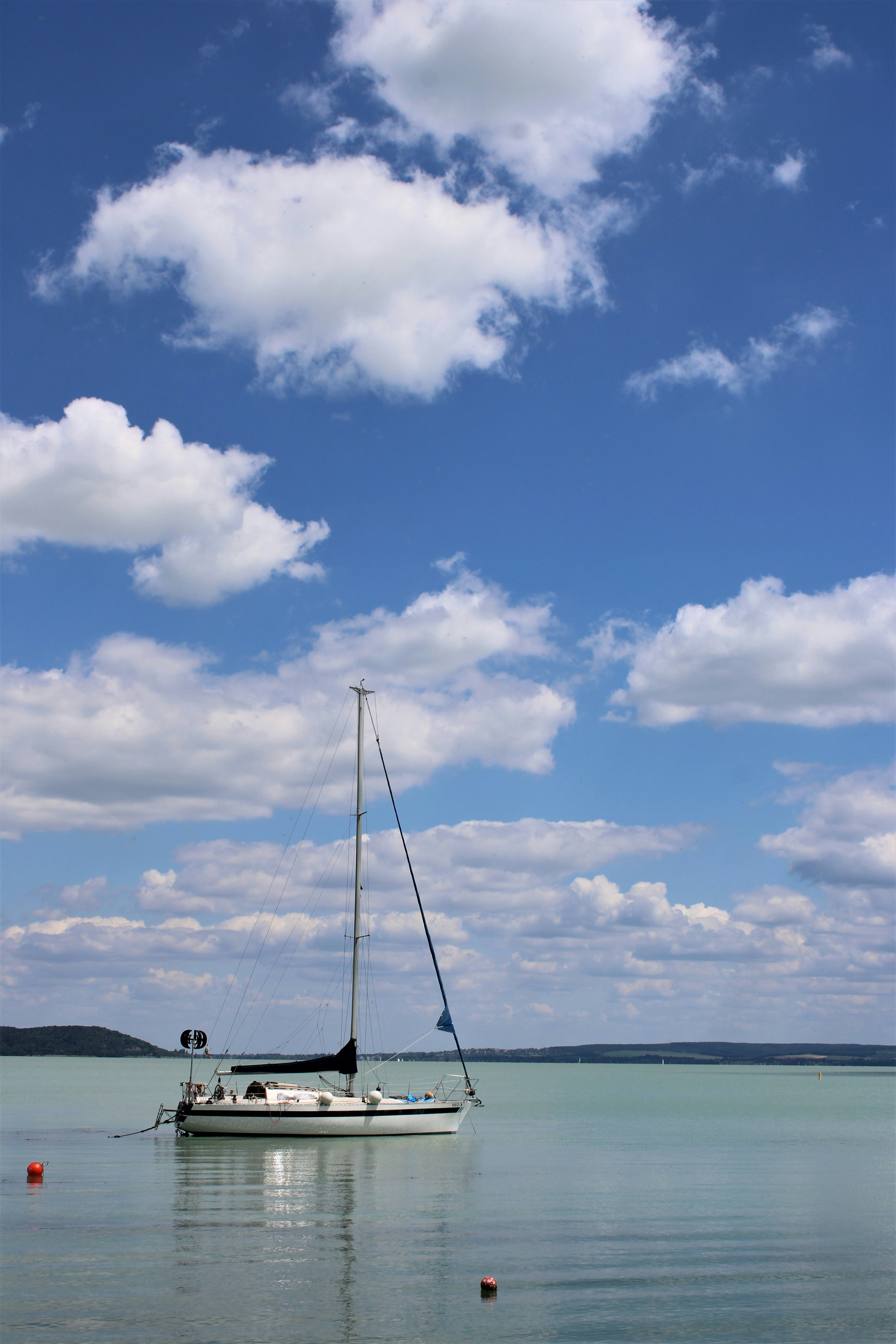 Lone Sailboat on a Glassy Gulf Under a Puffed-Cloud Sky