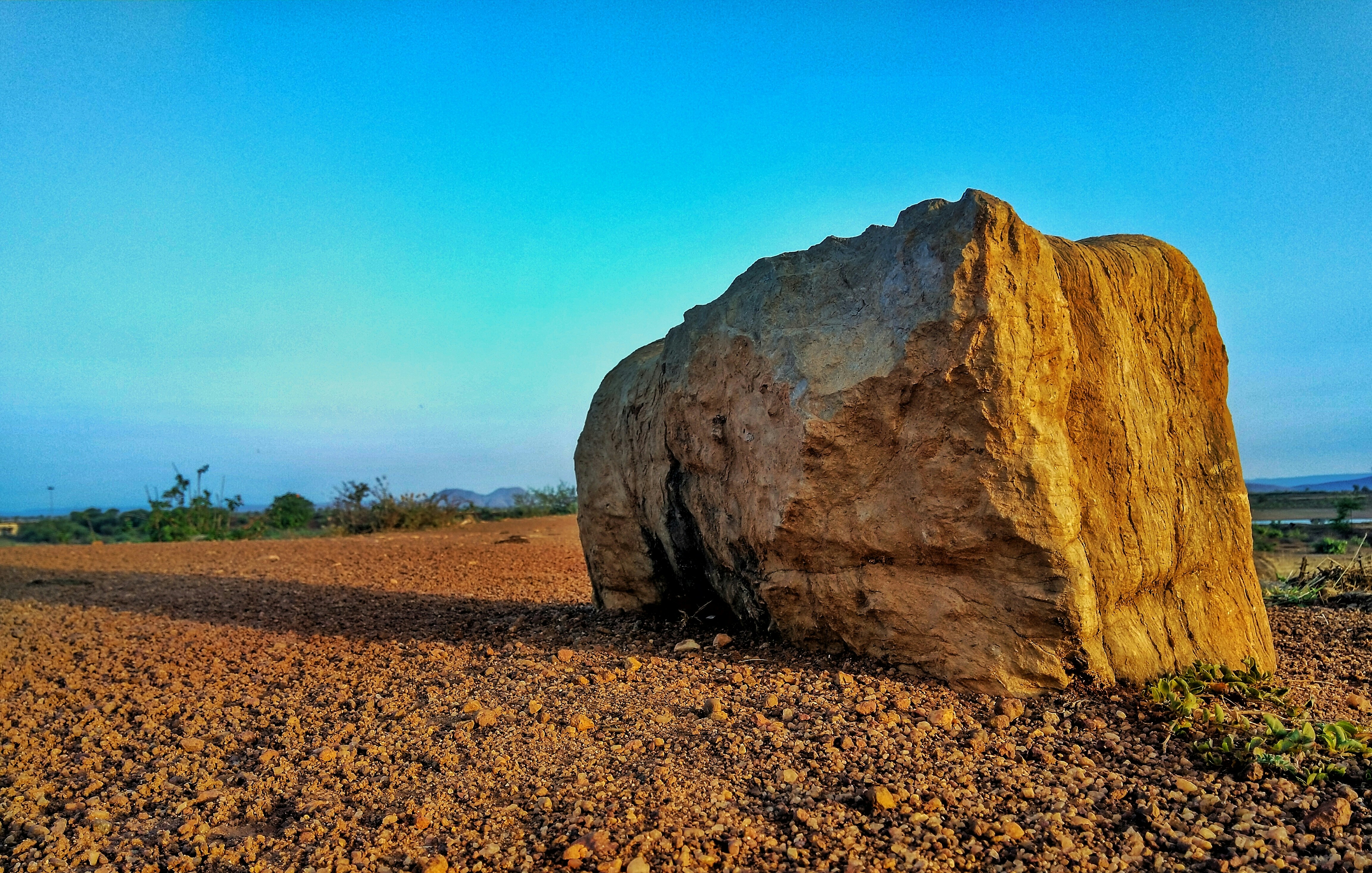 Sunlit Sentinel: A Desert Rock Standing Against the Blue Sky