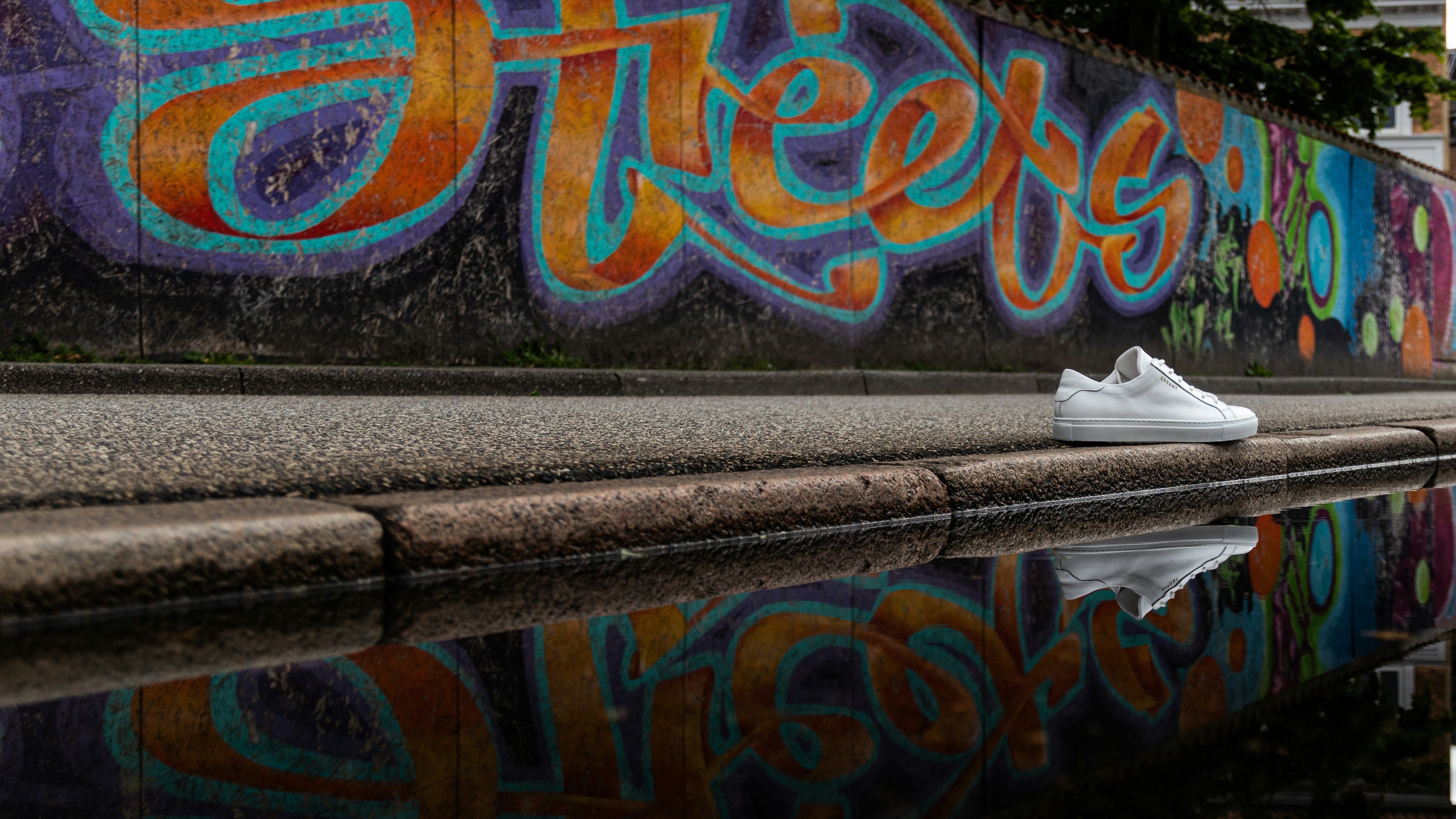 Sole on the Slick Edge: White Sneaker Against a Graffiti Wall