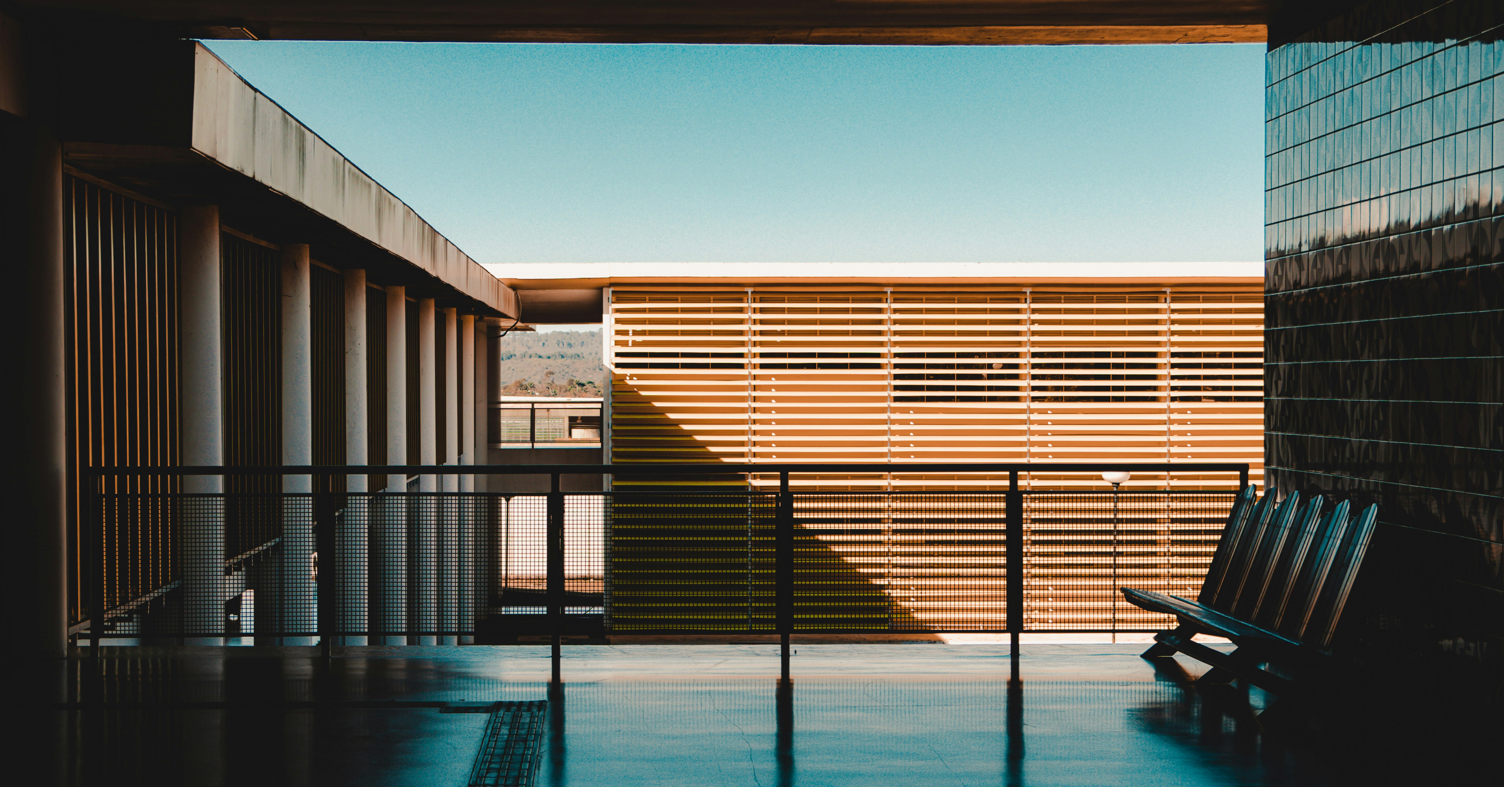 Contemporary building facade with geometric patterns and a bench in the foreground under a clear sky.
