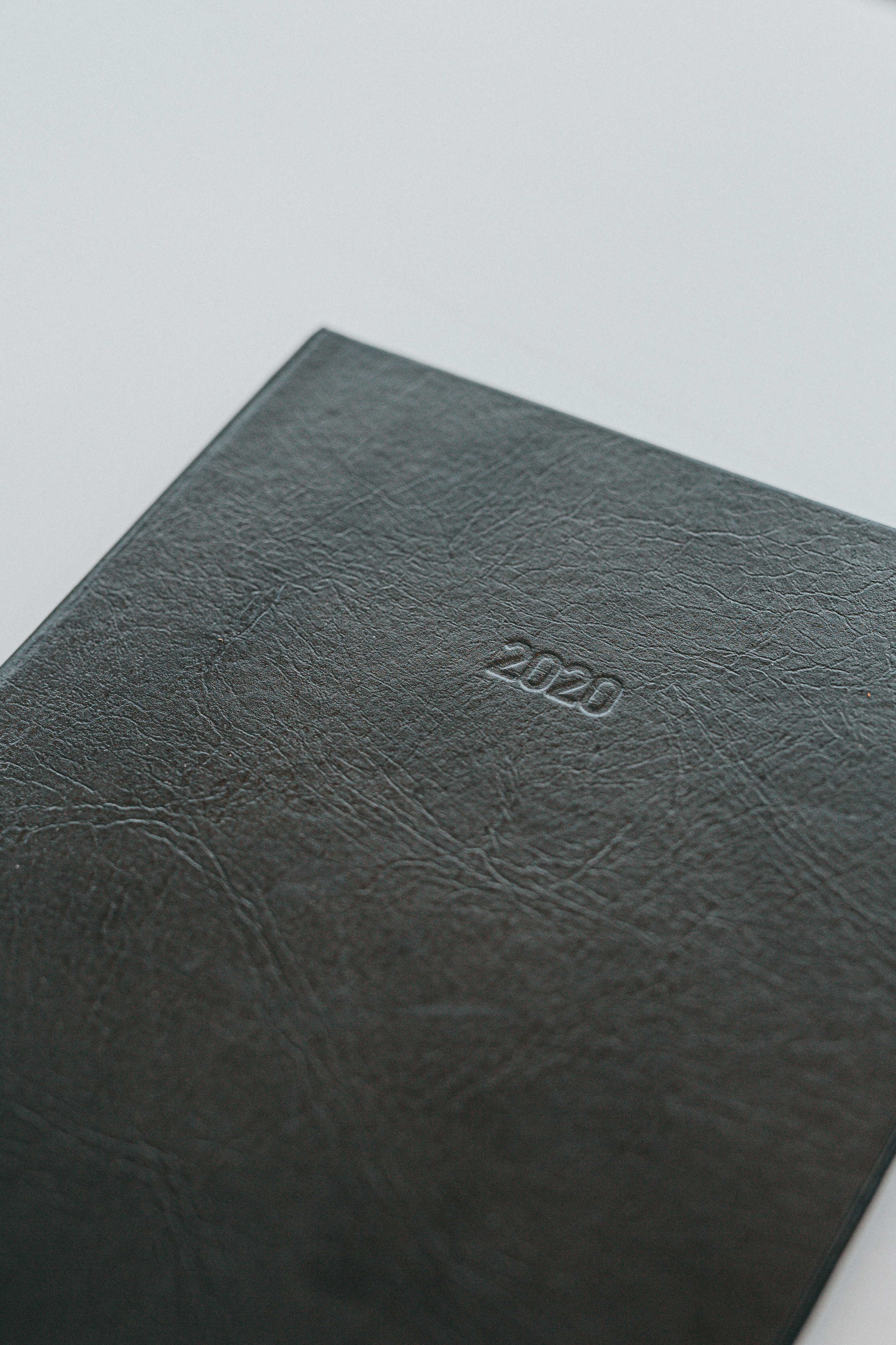Black leather journal embossed with the year '2020' on the cover, resting on a light surface.