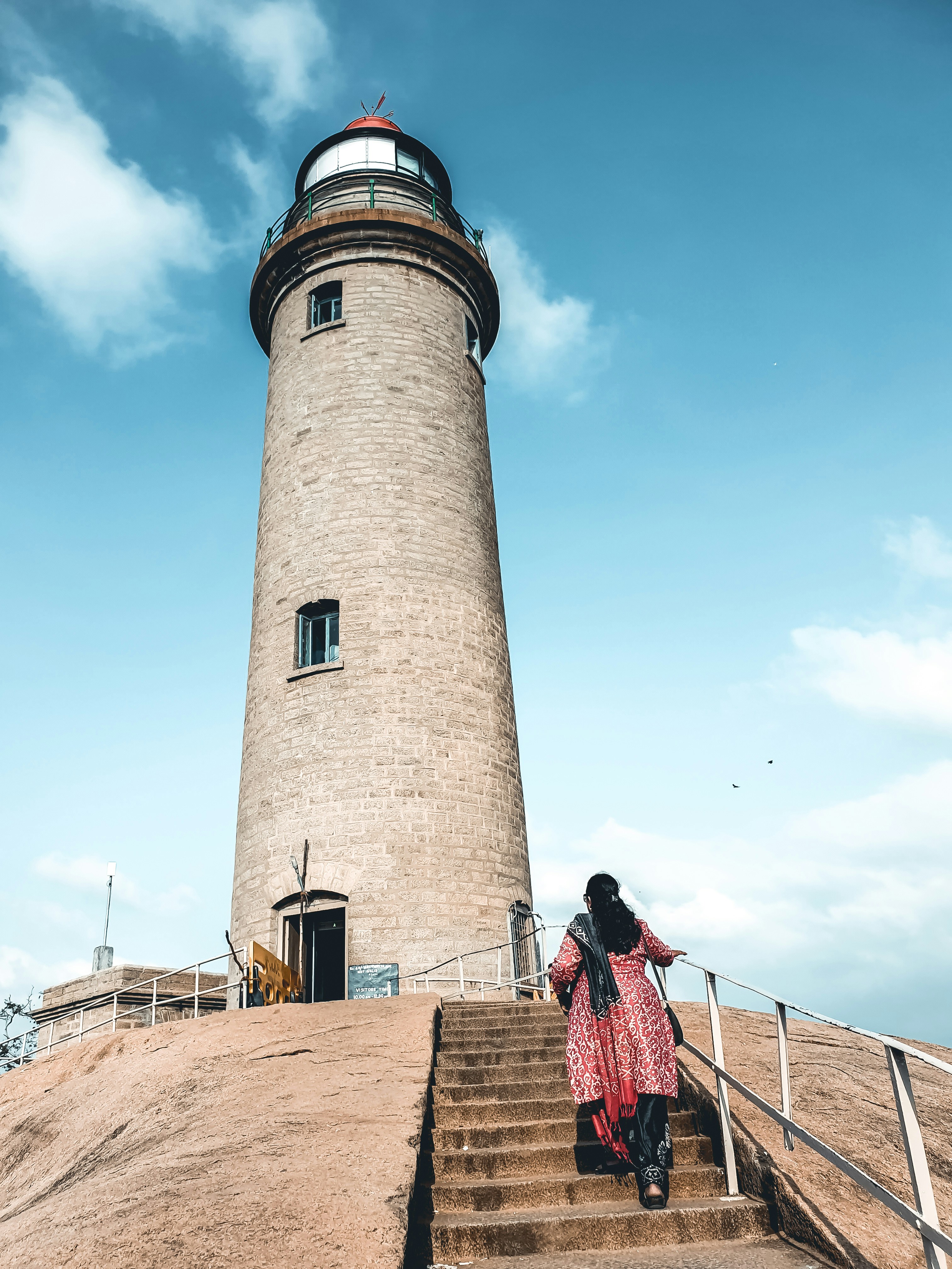 Beacon Ascent: A Traveler Climbing the Lighthouse Steps Under a Sharp Blue Sky