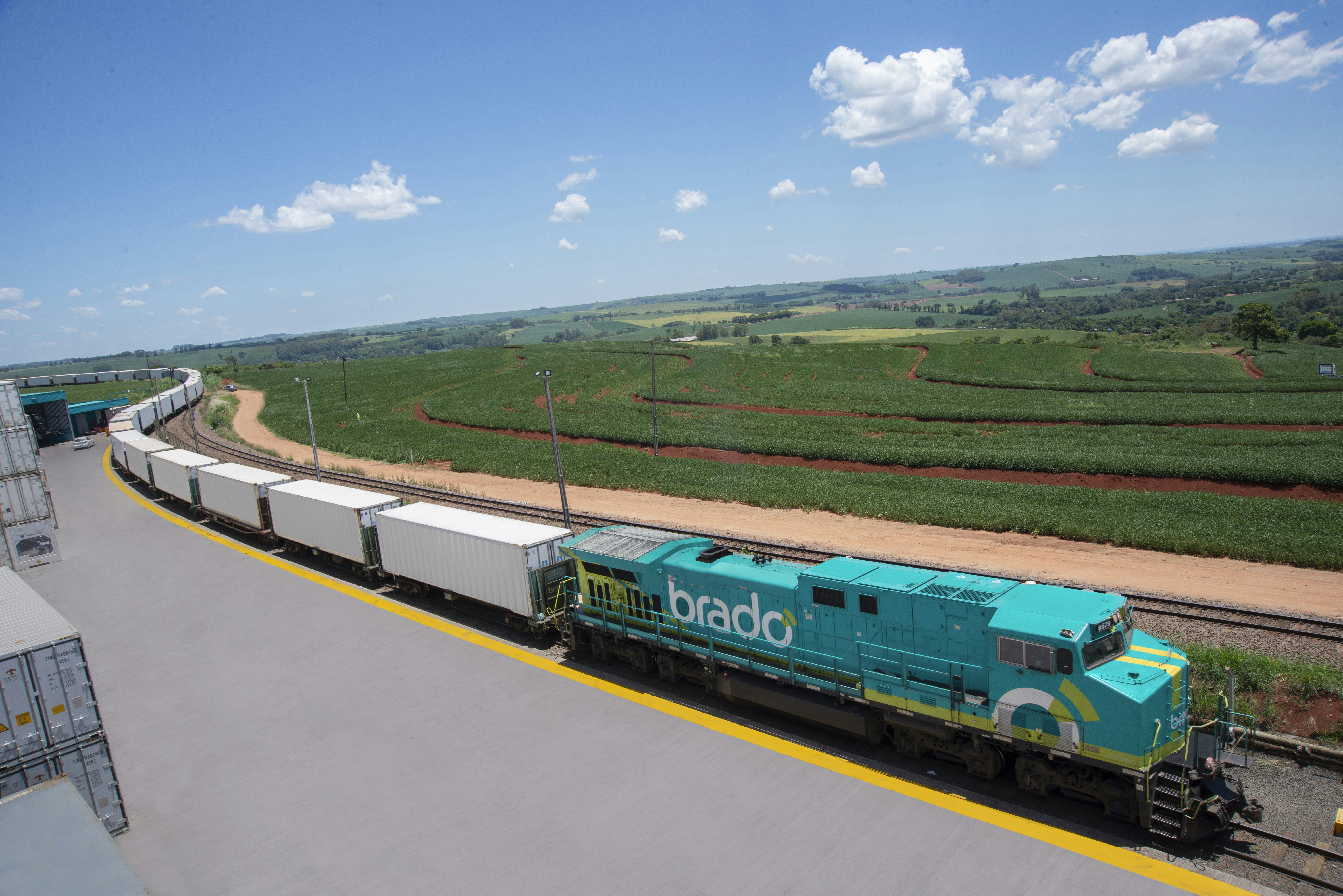 Bright turquoise locomotive at the curve: Brado freight train along sunlit rails
