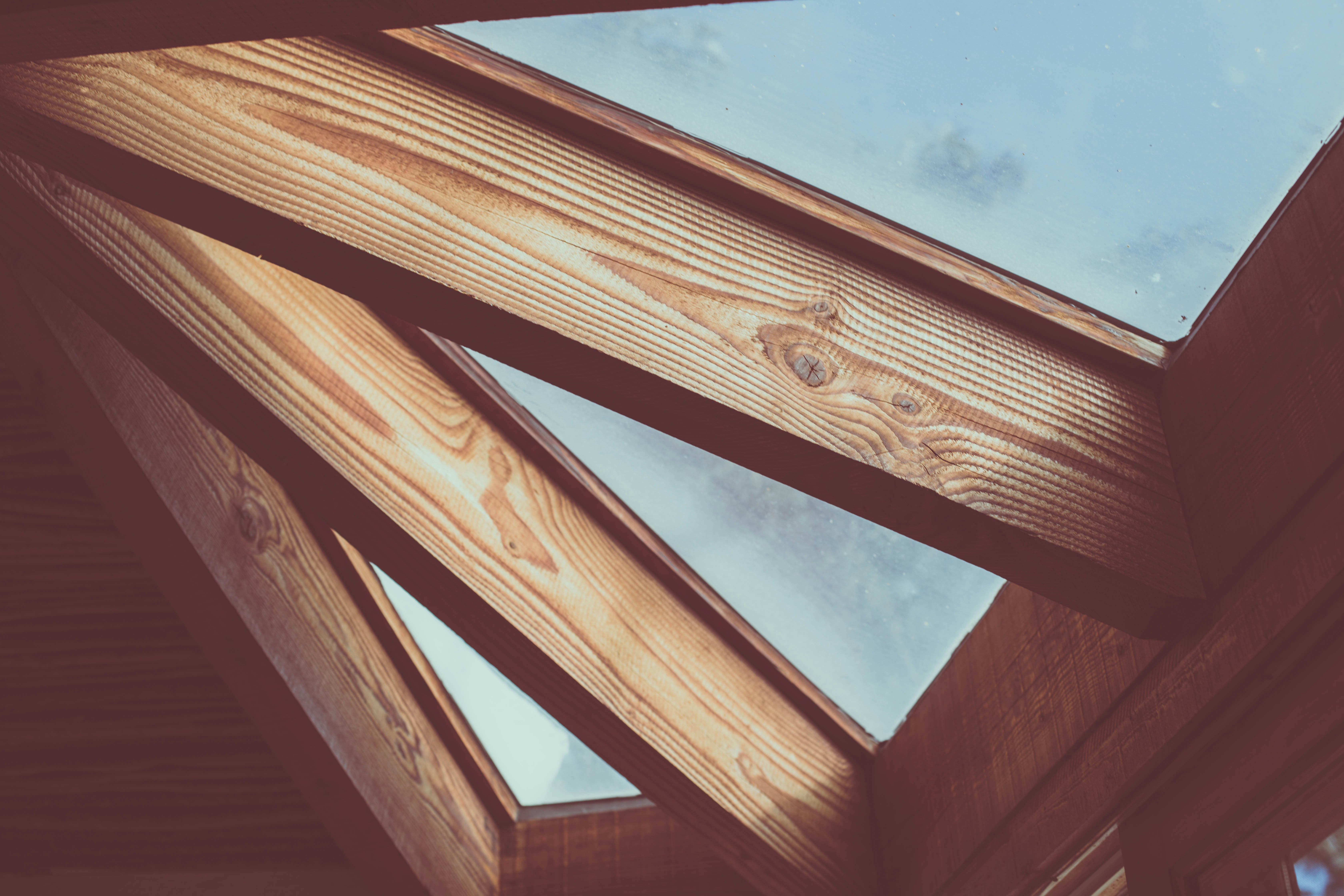 Wooden beams of a skylight frame contrasting with the sky, highlighting the blend of architecture and nature.