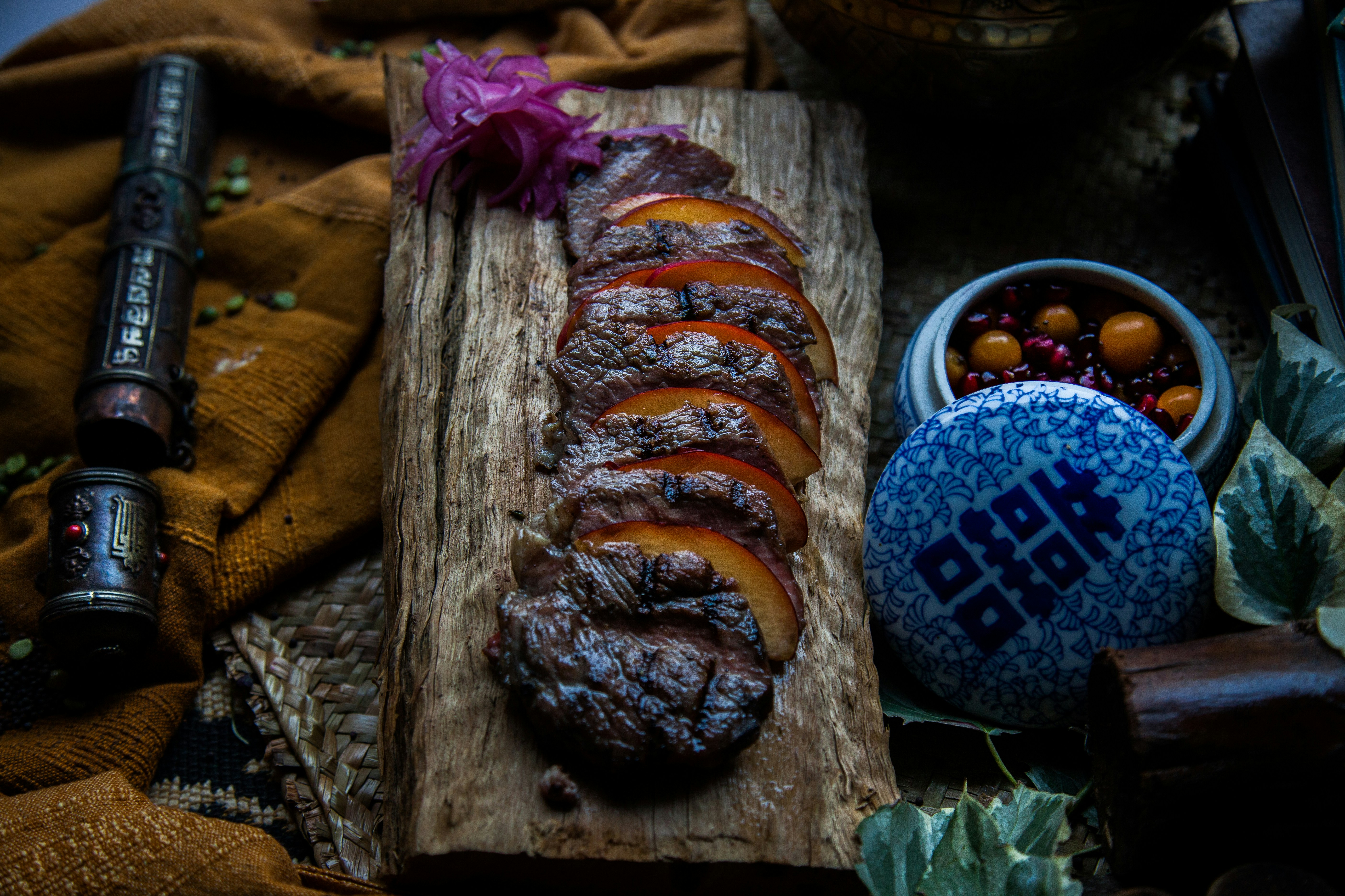 Ember-Toned Roast Slices Rest on Weathered Board, with a Blue BBQ Motif and Rustic Props
