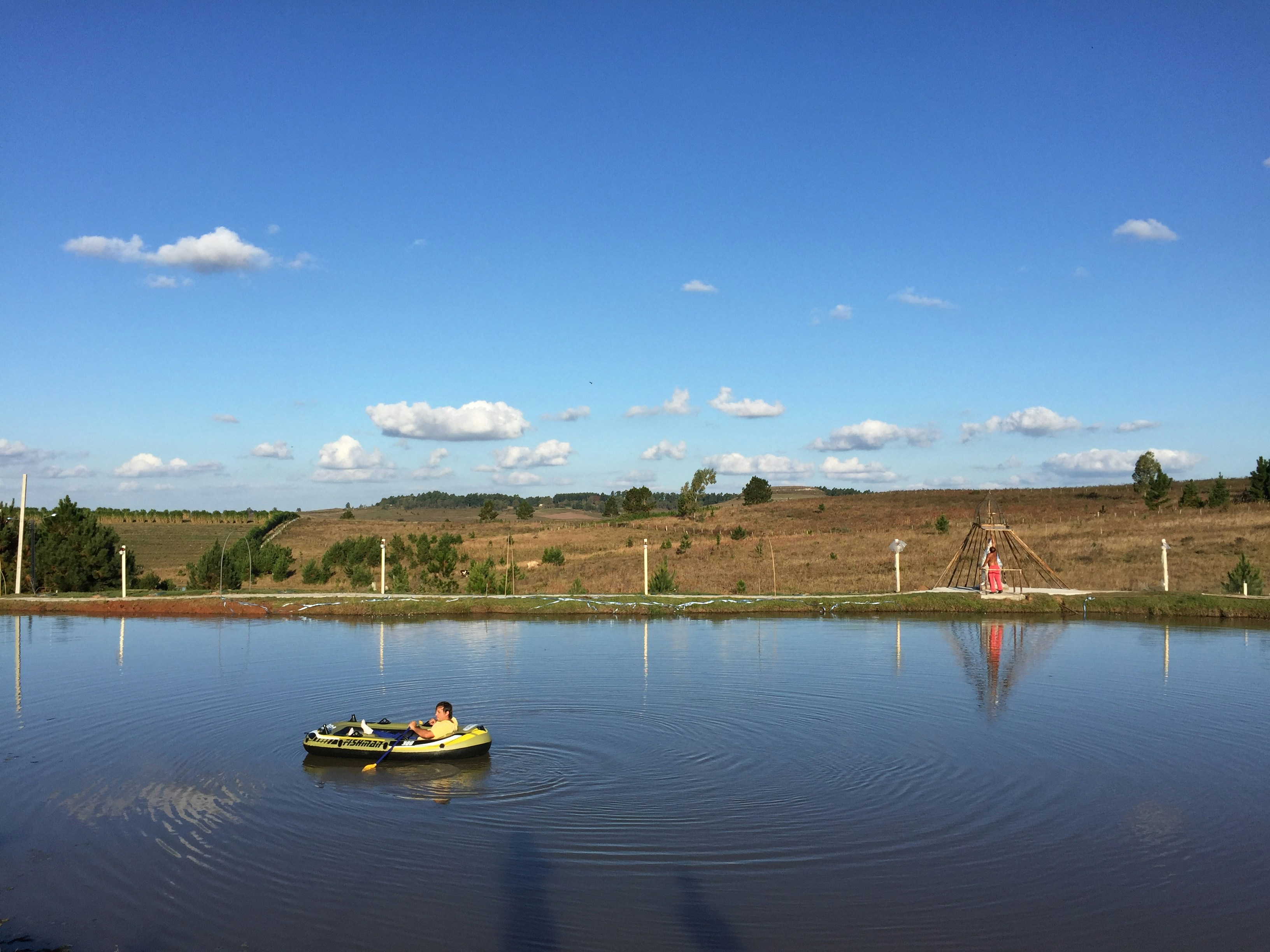 Lone Inflatable Boat on a Glassy Lake Under a Broad Blue Sky