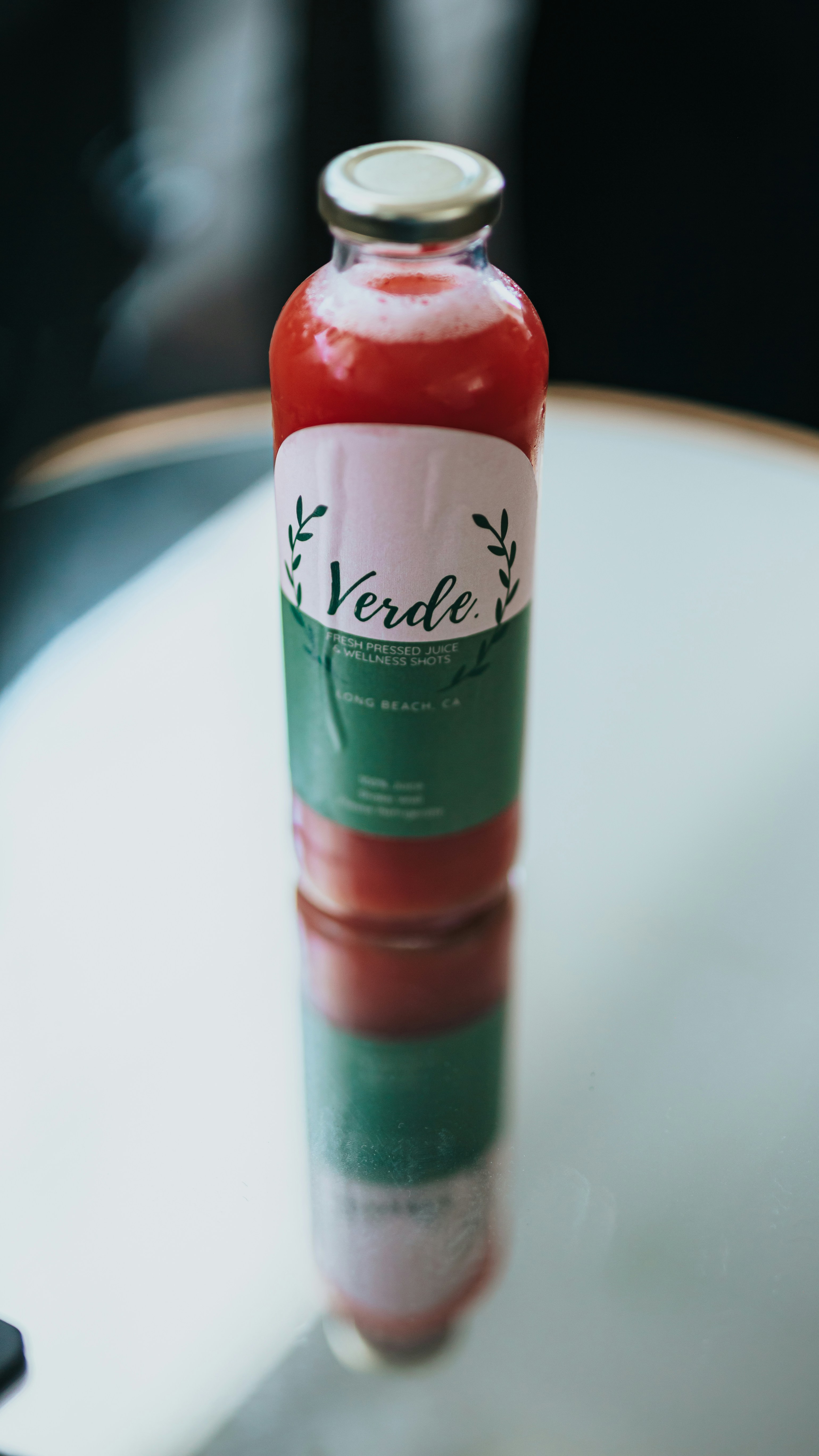 Vibrant Juice Bottle Stands Tall on a Reflective Table