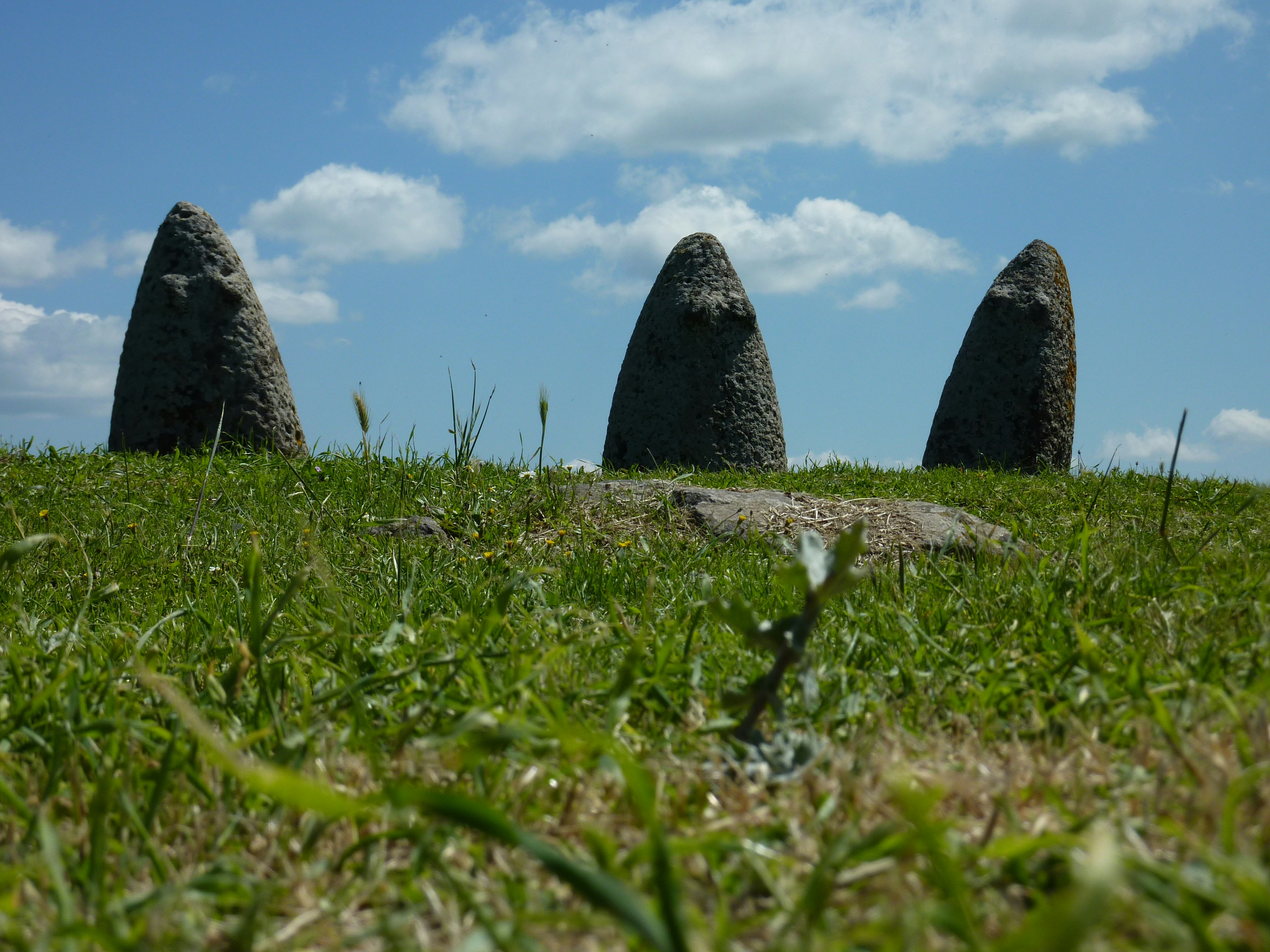 Three Stone Pillars on a Sunlit Grass Hill