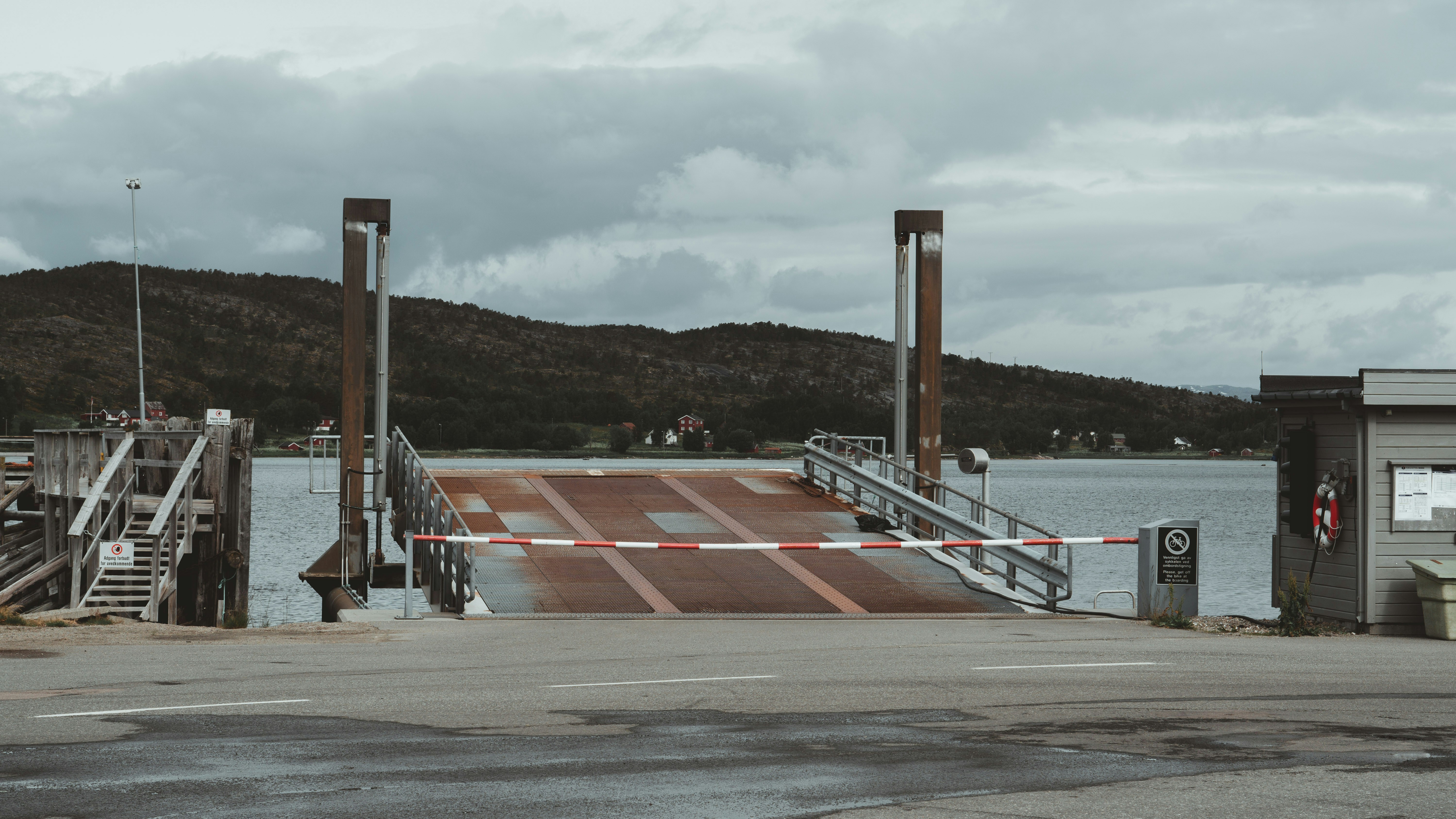 A serene dock extending into calm waters, framed by distant hills under a cloudy sky.