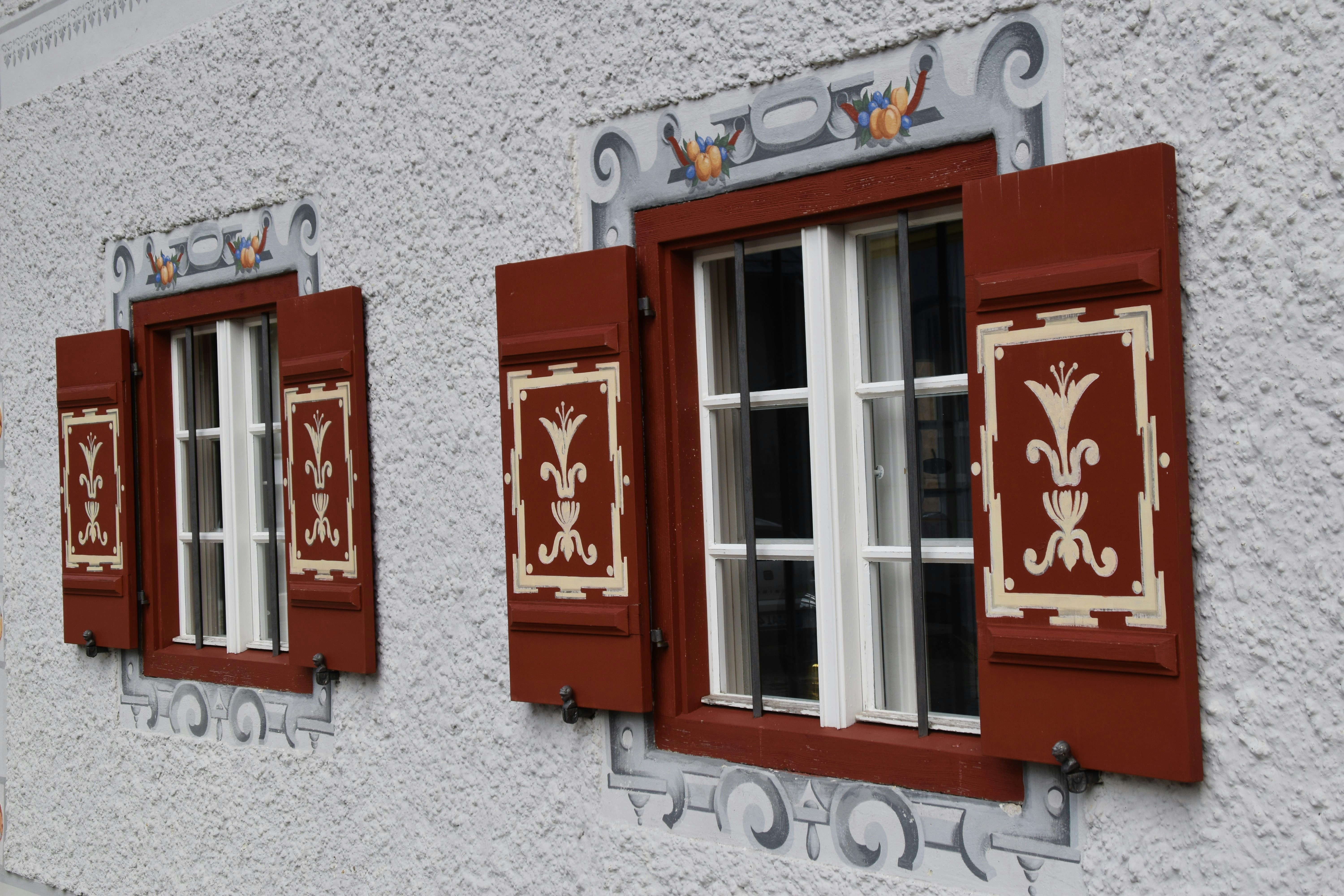 The Quiet Facade: Red Shutters Framing a Textured White Wall