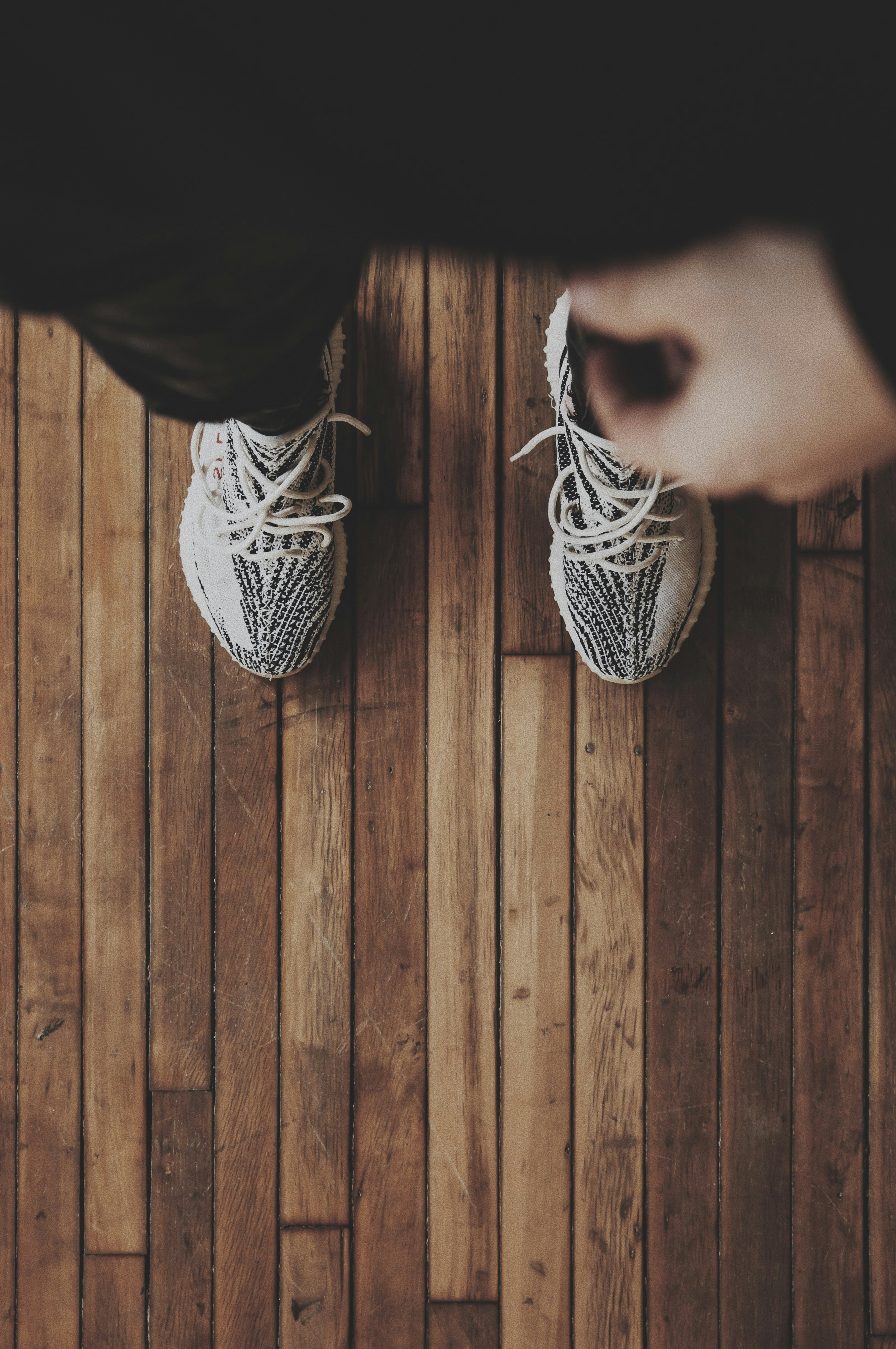 Black and white sneakers on a rustic wooden floor.