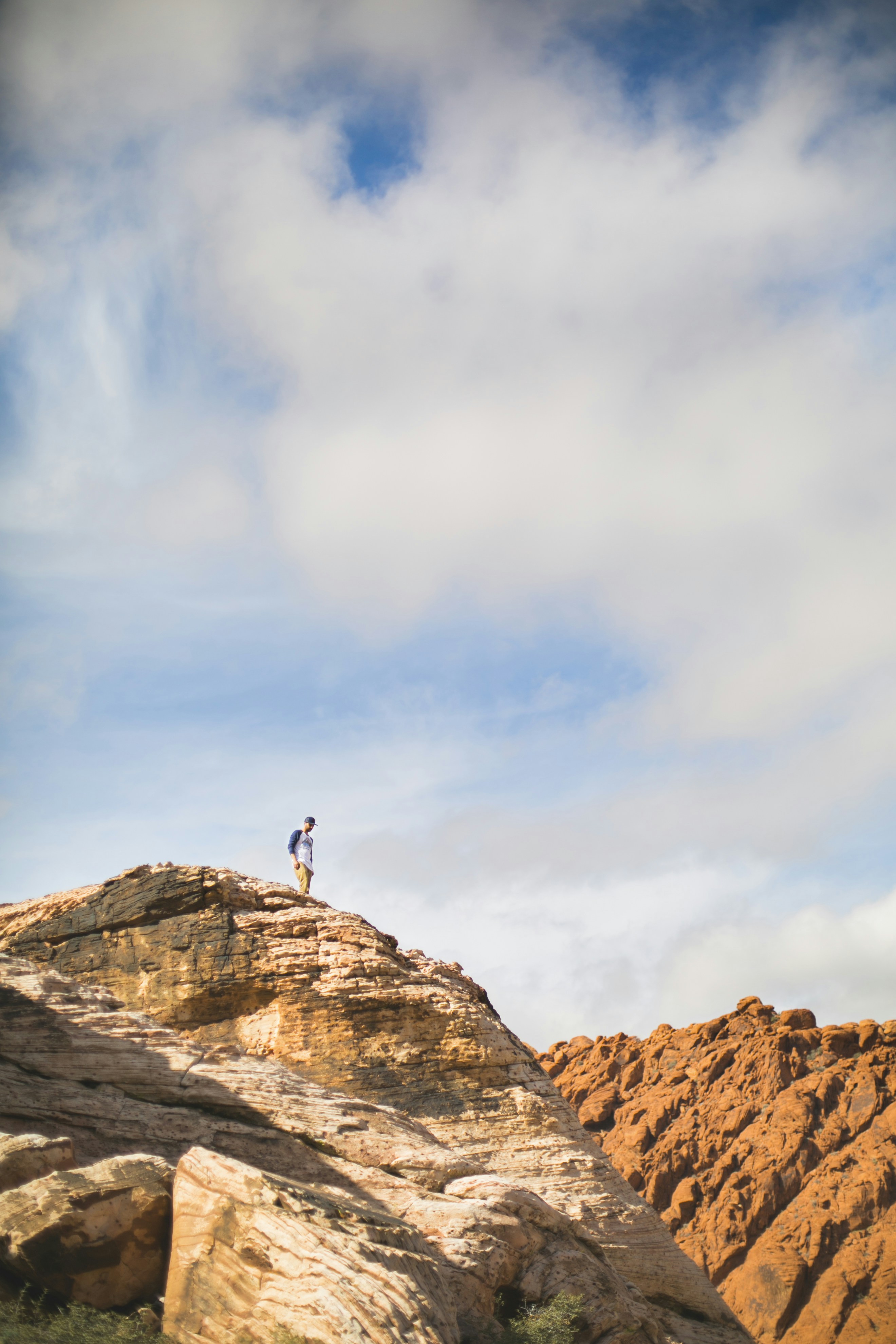 Person standing on brown rock formation under white clouds and blue sky ...