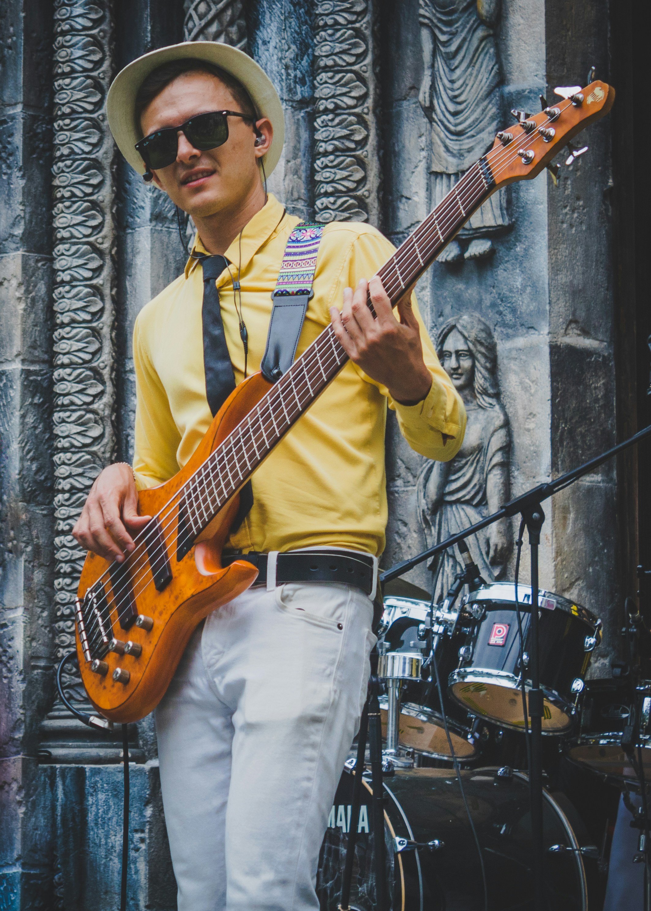 Groove Beneath the Carved Facades: A Yellow-Suited Bassist in Sunlit Focus