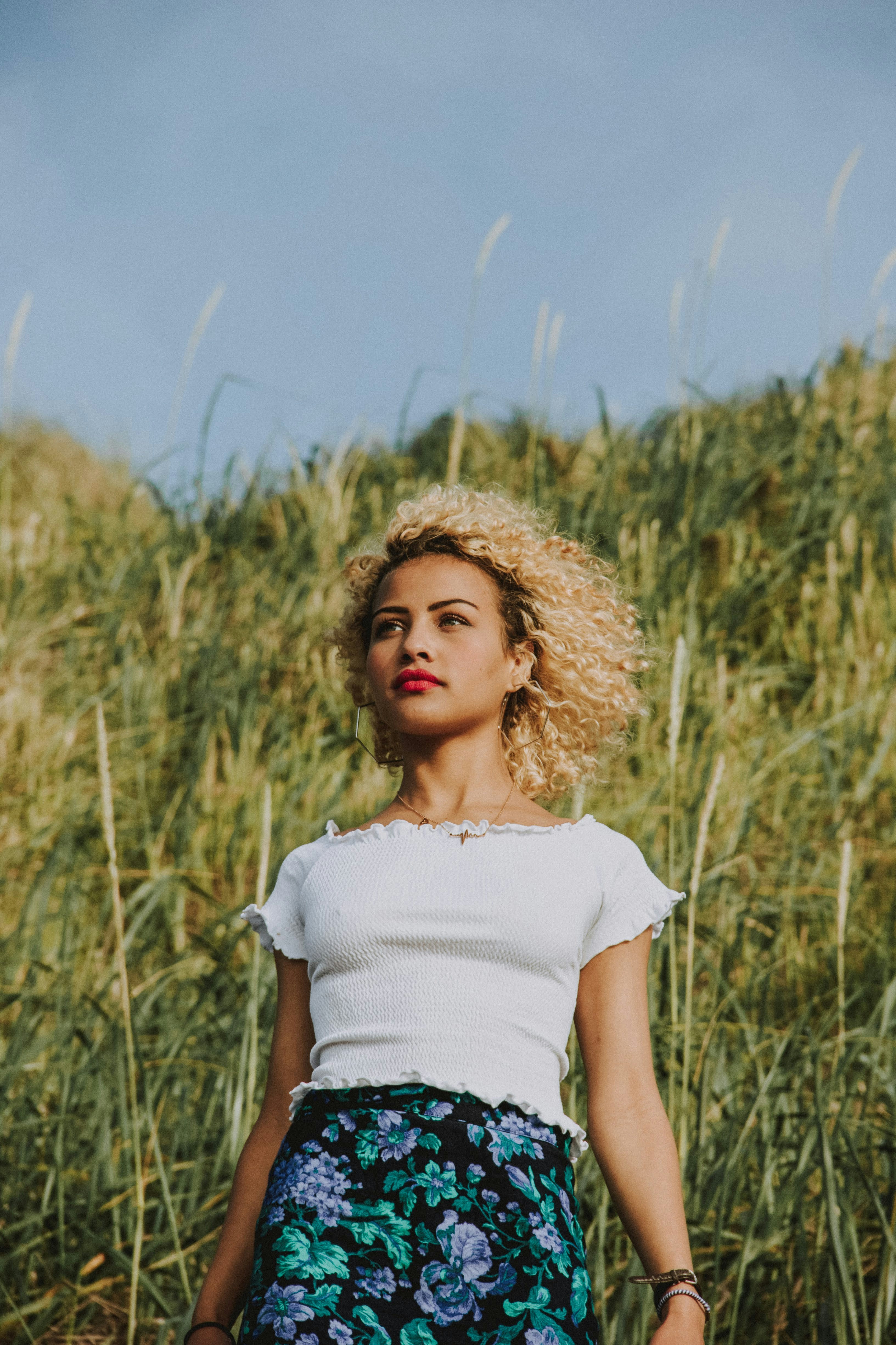 Young woman stands confidently amidst tall grass, exuding a sense of tranquility and strength.