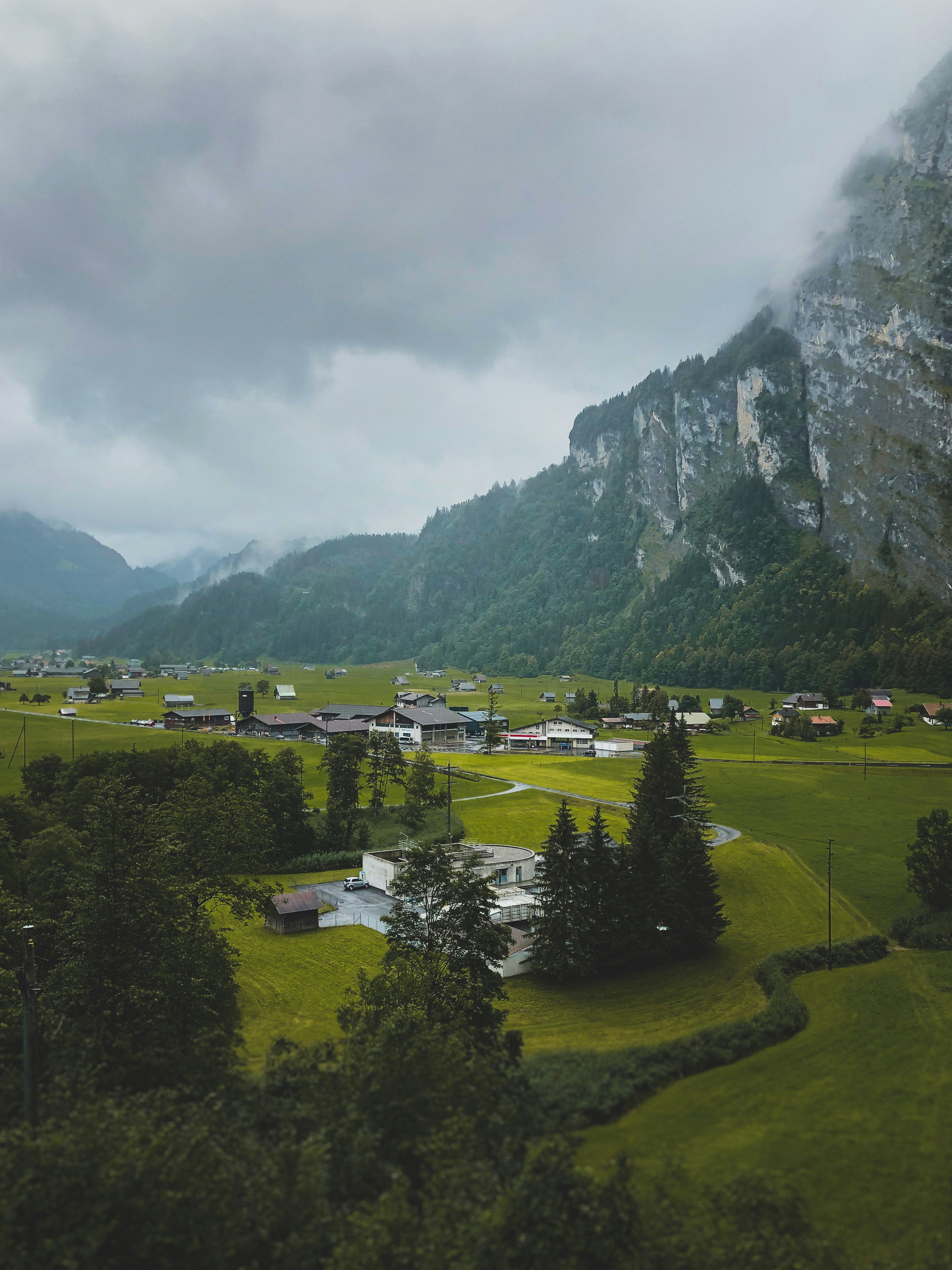 Village in a Mist-Wrapped Alpine Valley Under Cloud-Draped Cliffs