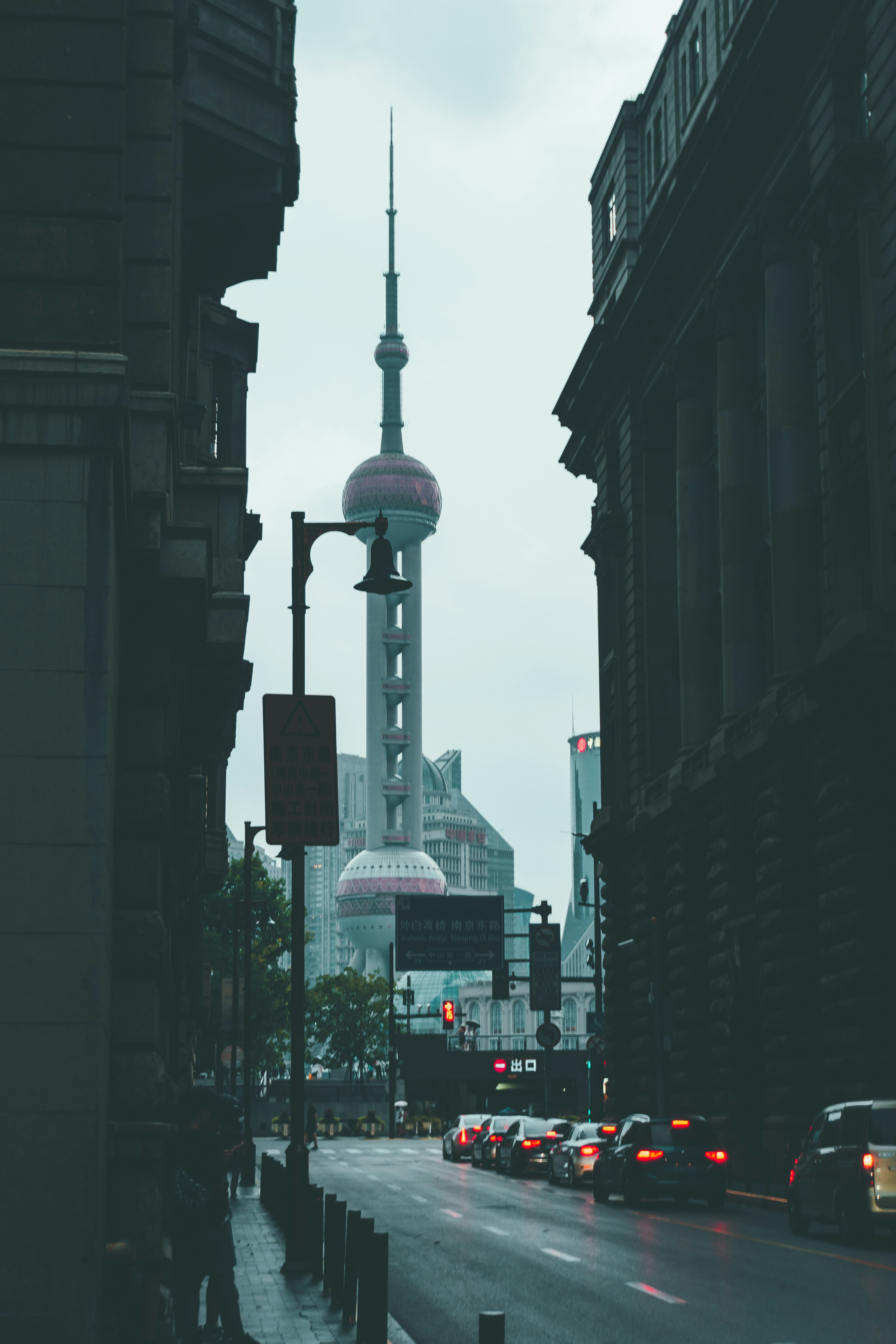 The Oriental Pearl Tower rises majestically amidst historic architecture, framed by a moody sky. Street scenes hint at the vibrant life of the city.