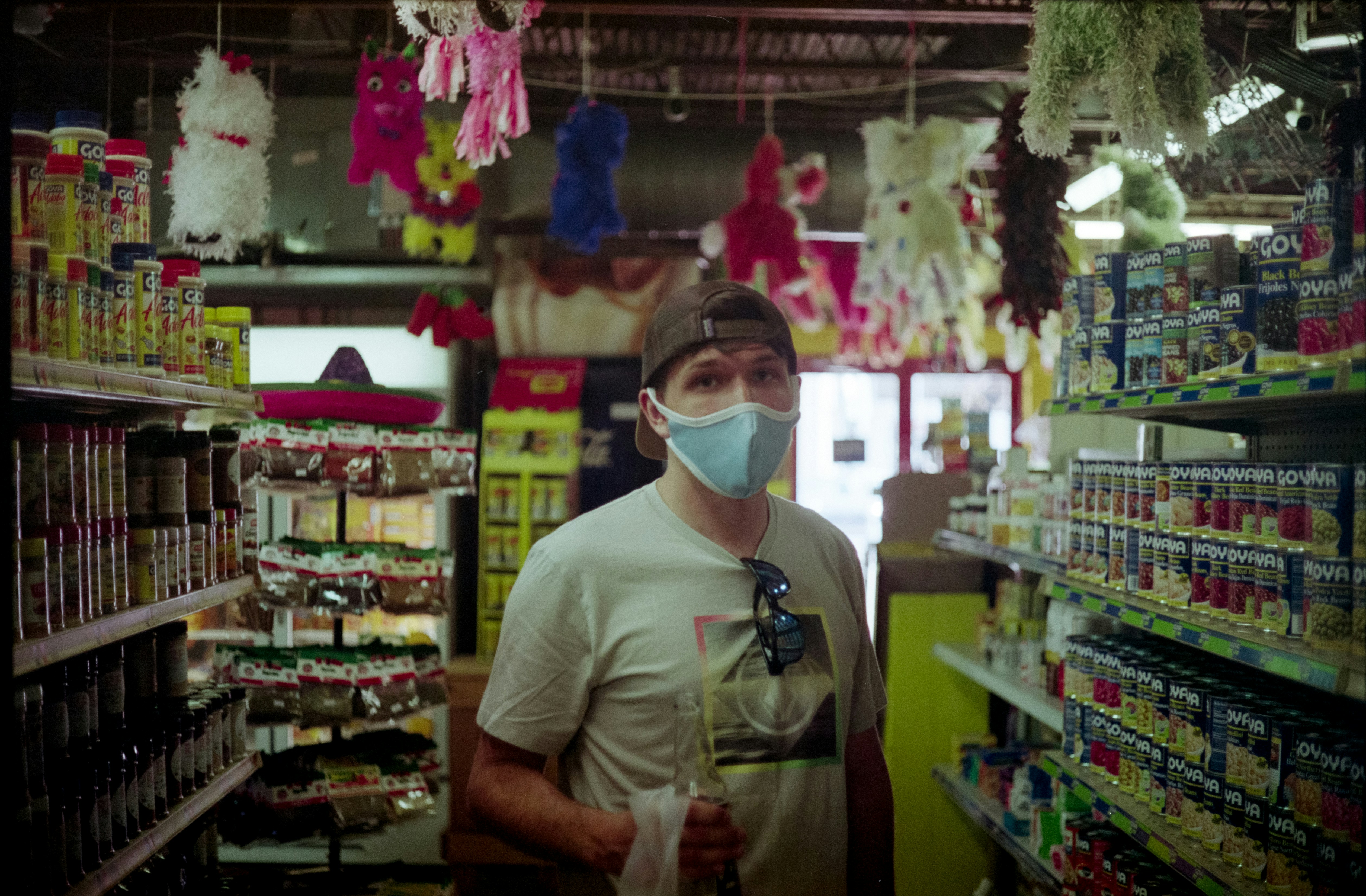 Masked shopper in a colorful aisle: a candid moment at the checkout