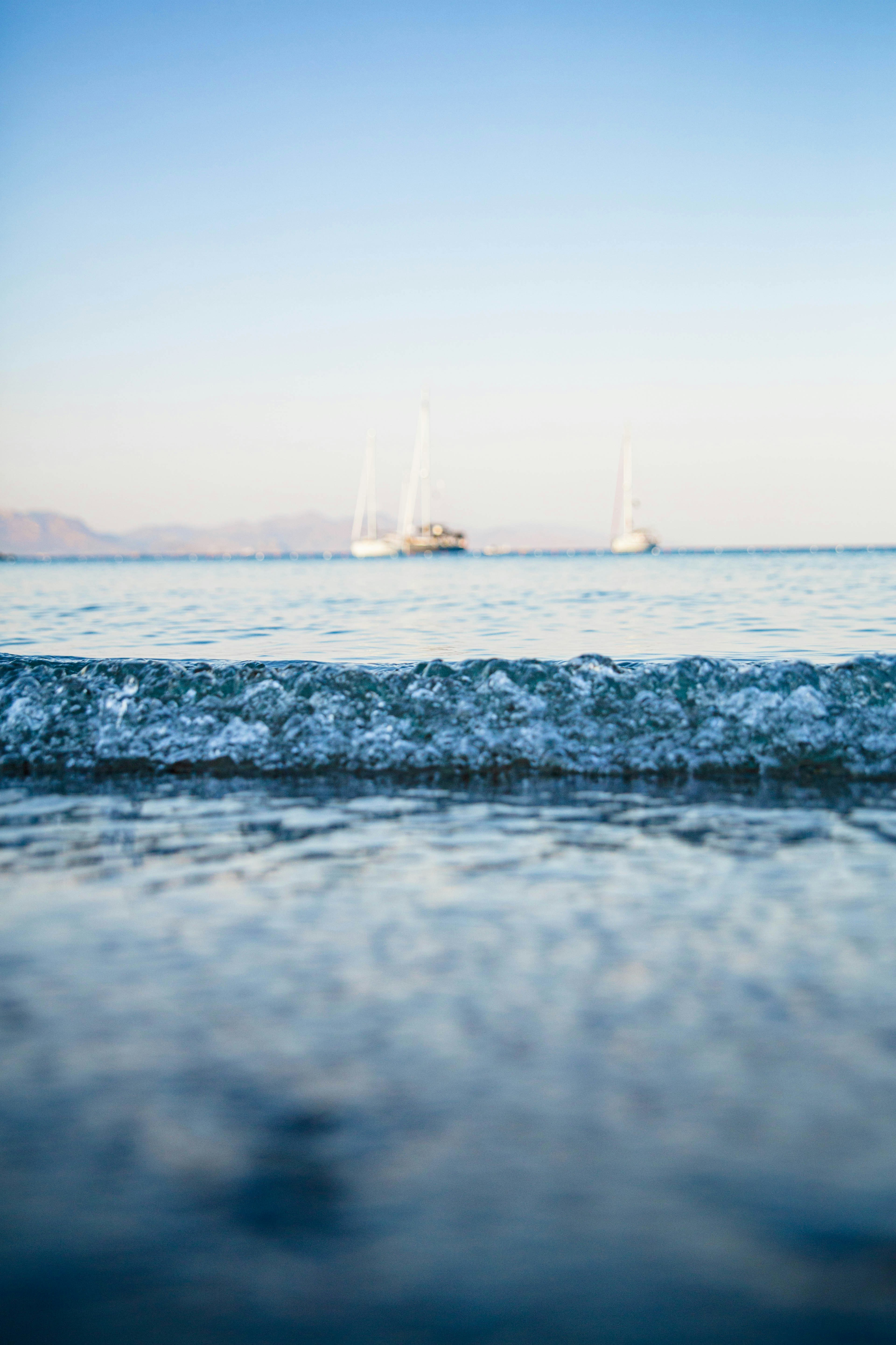 Foam at the Edge: A Quiet Shore with Distant Sails