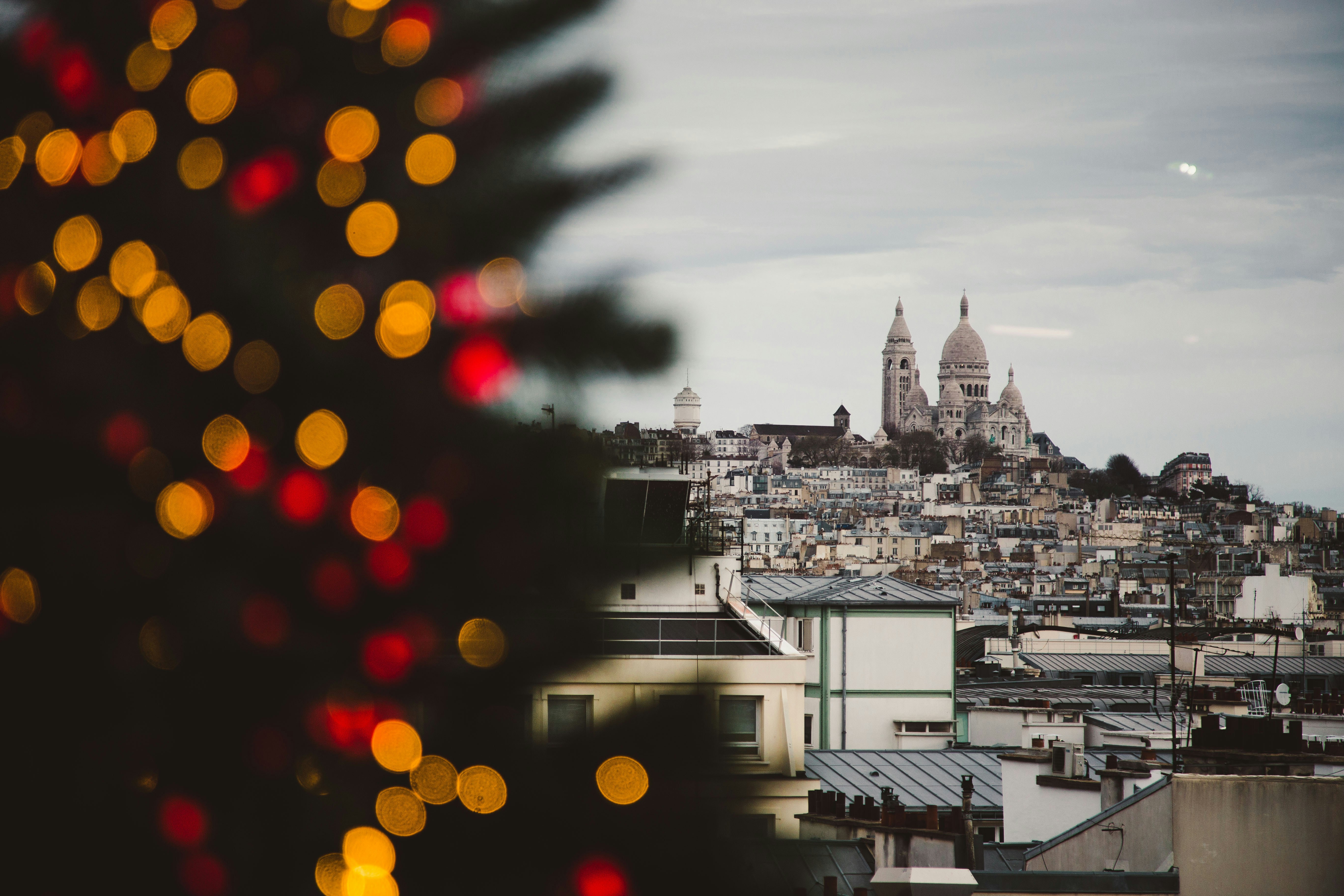 Sacre-Coeur Basilica atop Montmartre Hill with blurred festive lights in the foreground.