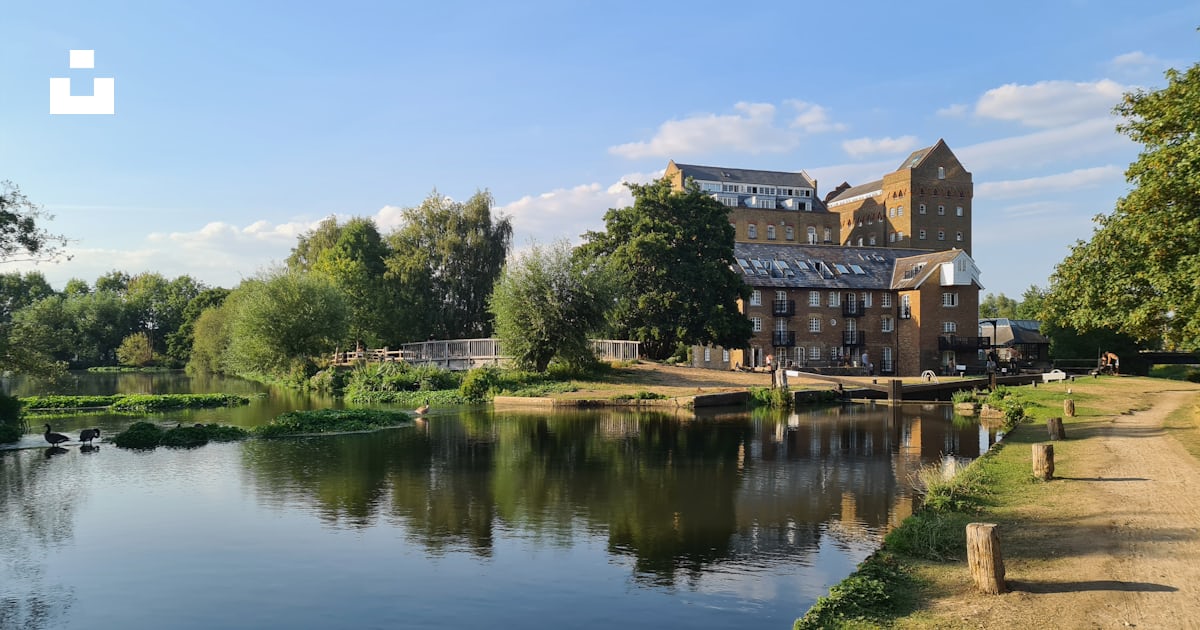 昼間の青空の下の湖の近くの茶色のコンクリートの建物の写真 Unsplashの無料イギリス写真